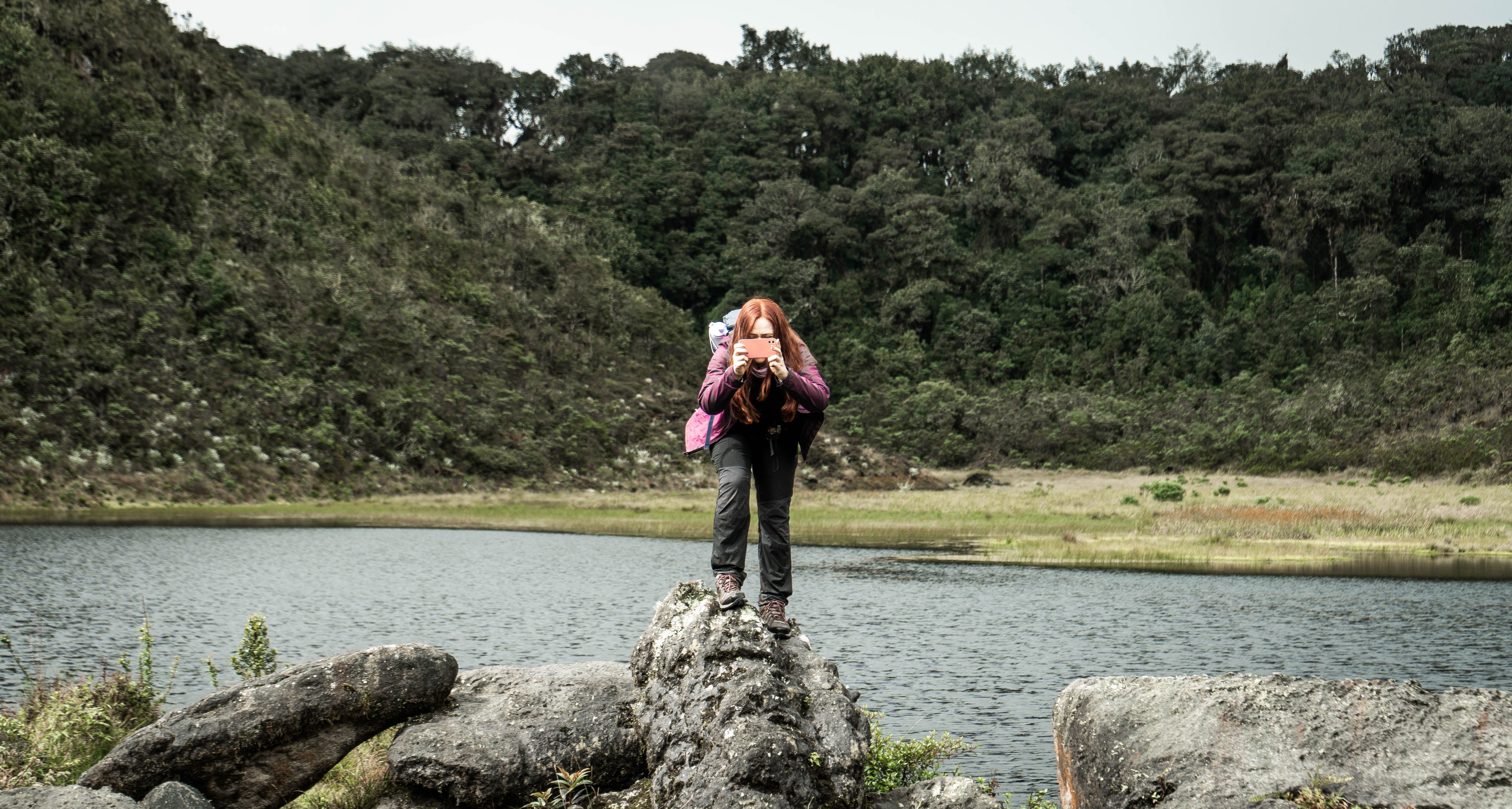 A Woman Standing on a Rock and Taking a Photo · Free Stock Photo