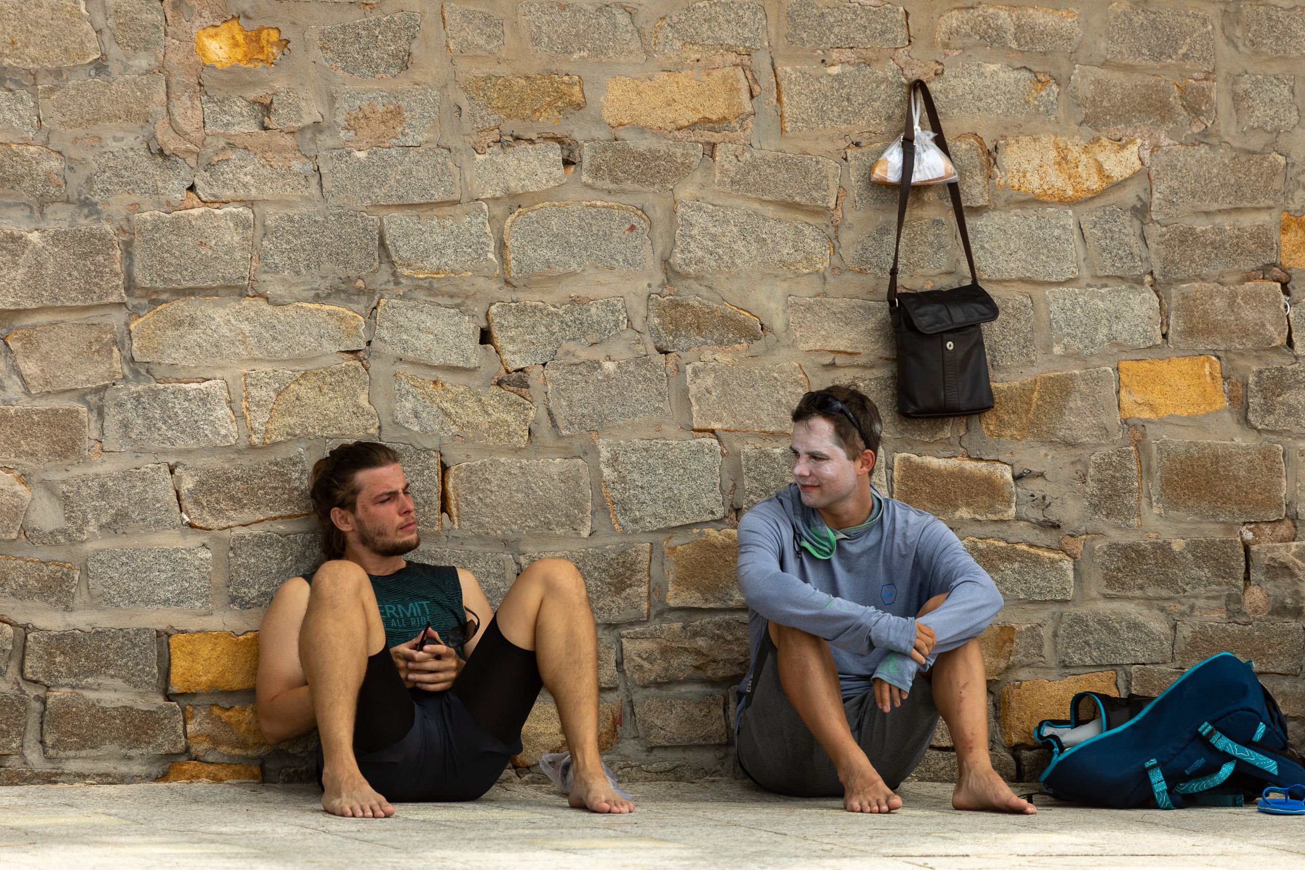 Young Men Sitting and Leaning against a Wall · Free Stock Photo