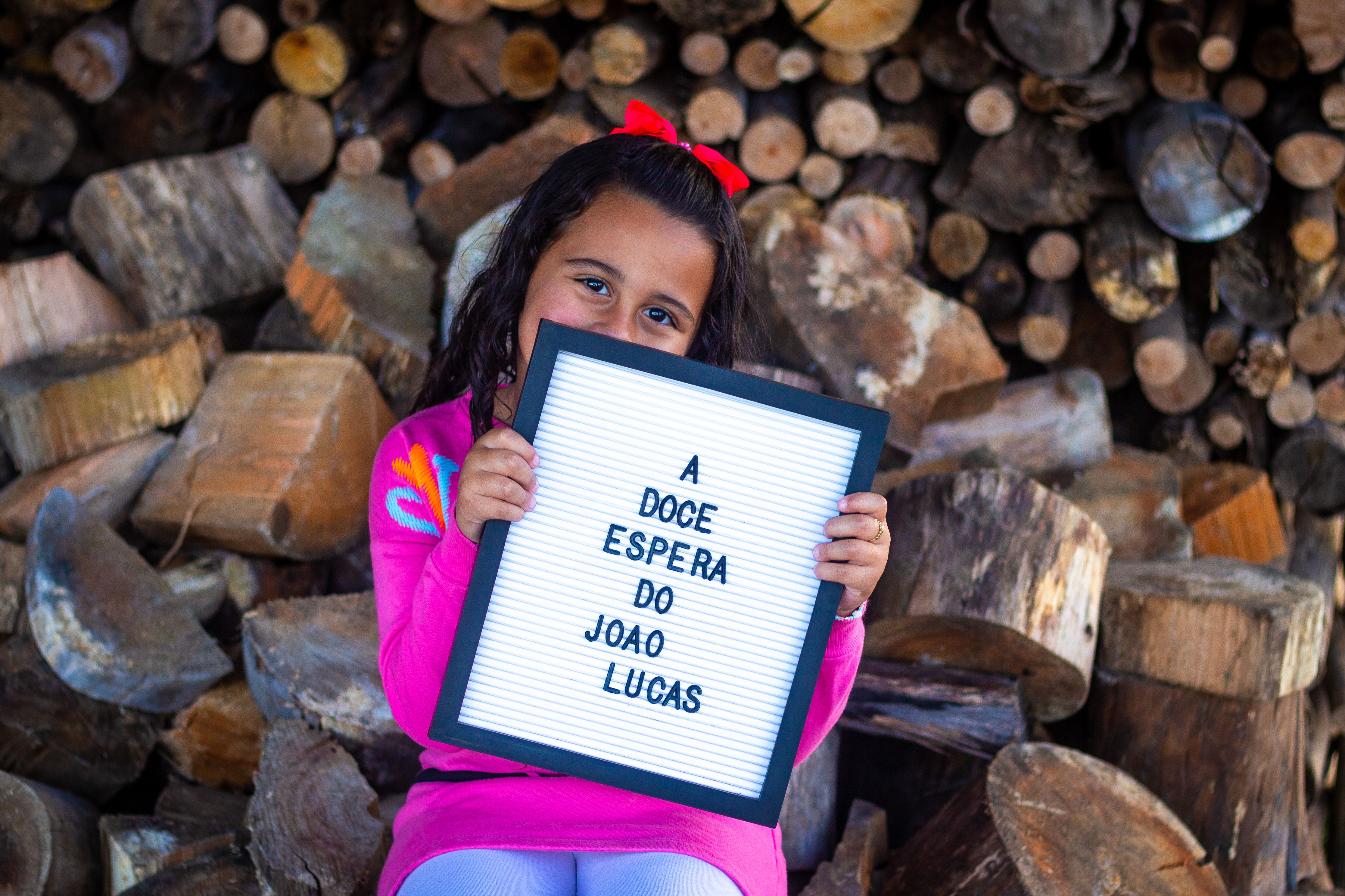 Girl Sitting on a Pile of Timber, Holding a Board with a Script · Free ...