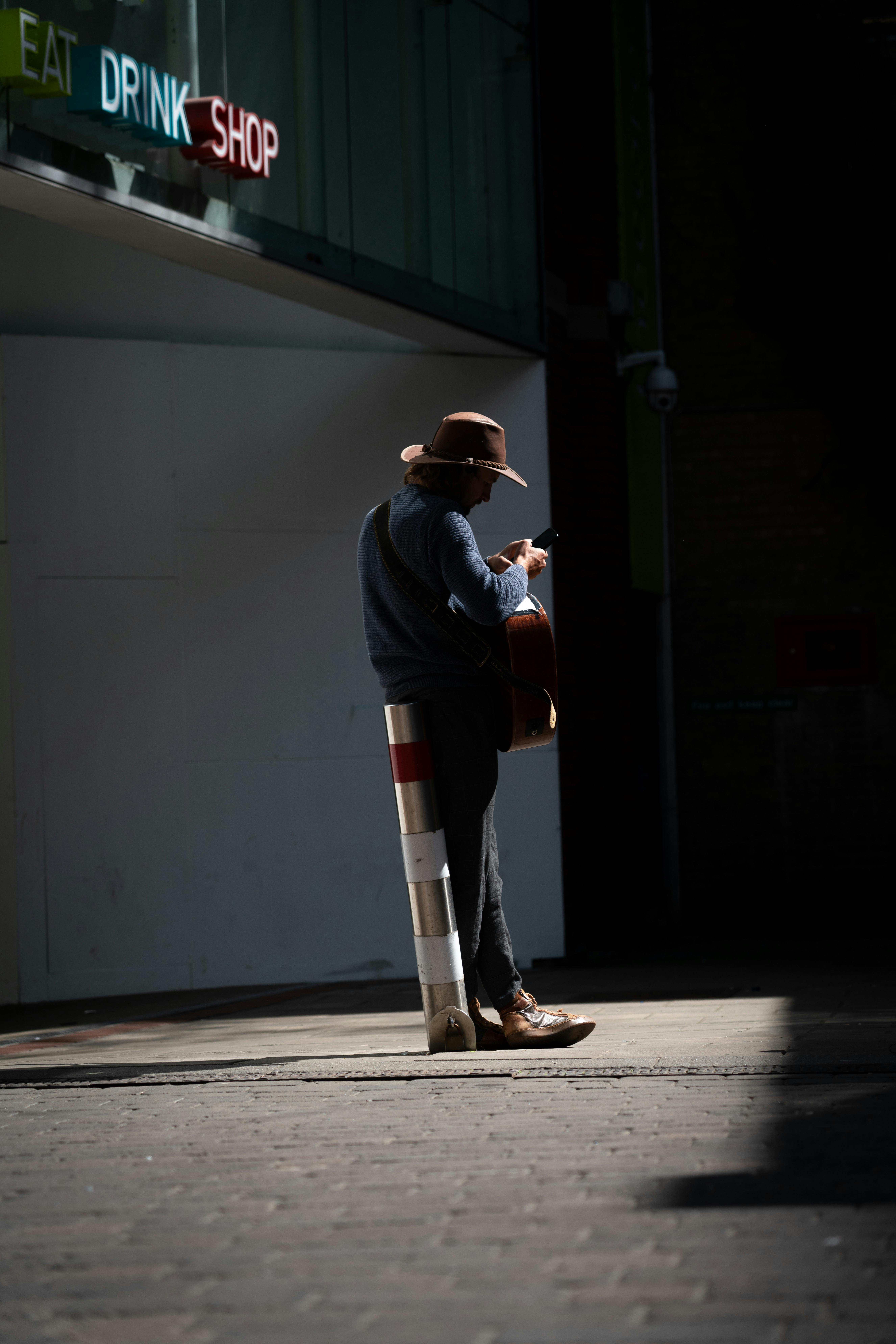 Man in a Wide Brim Hat Uses His Smart Phone Standing Propping Up on a ...