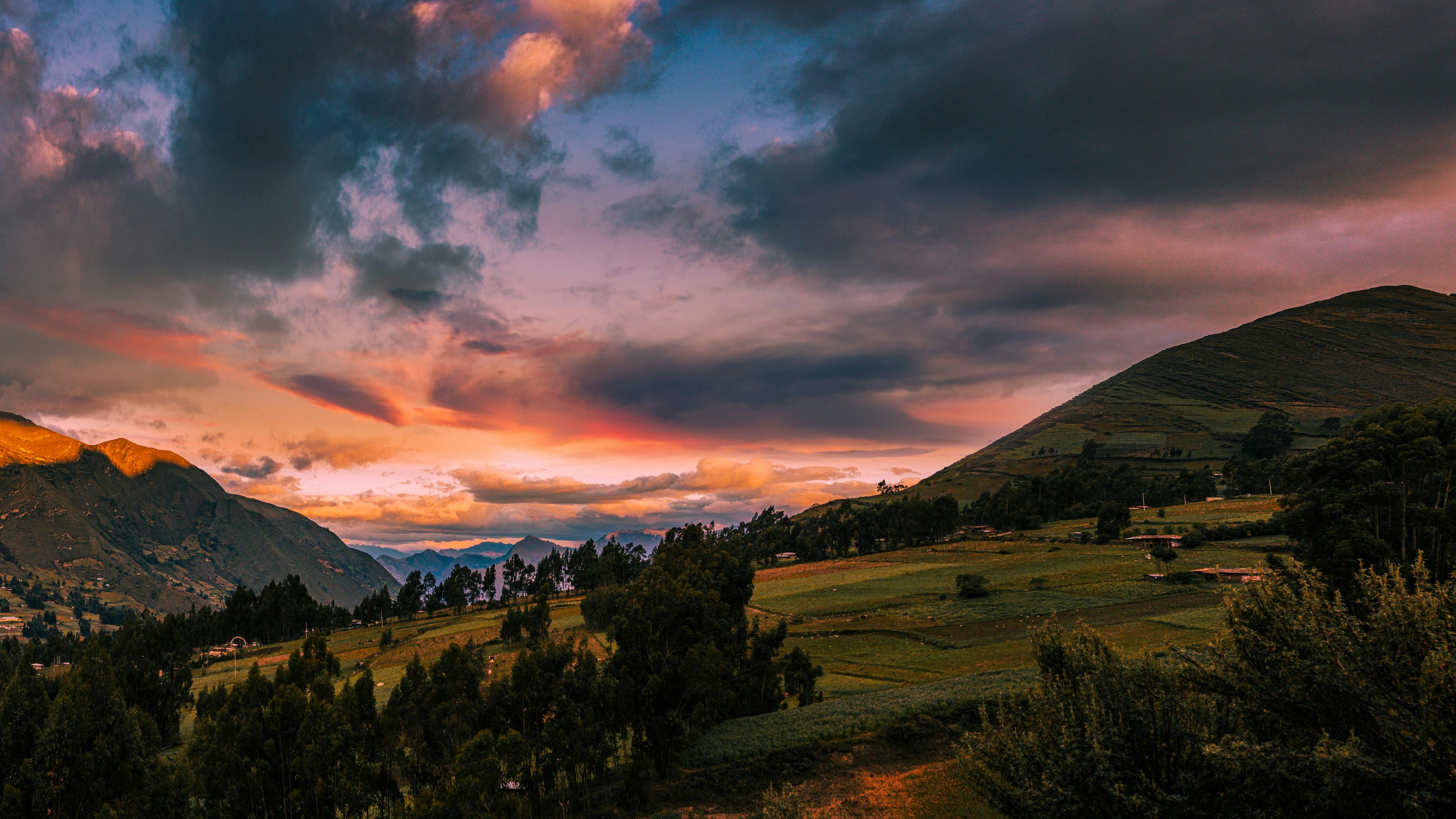 A sunset over a valley with mountains and clouds · Free Stock Photo