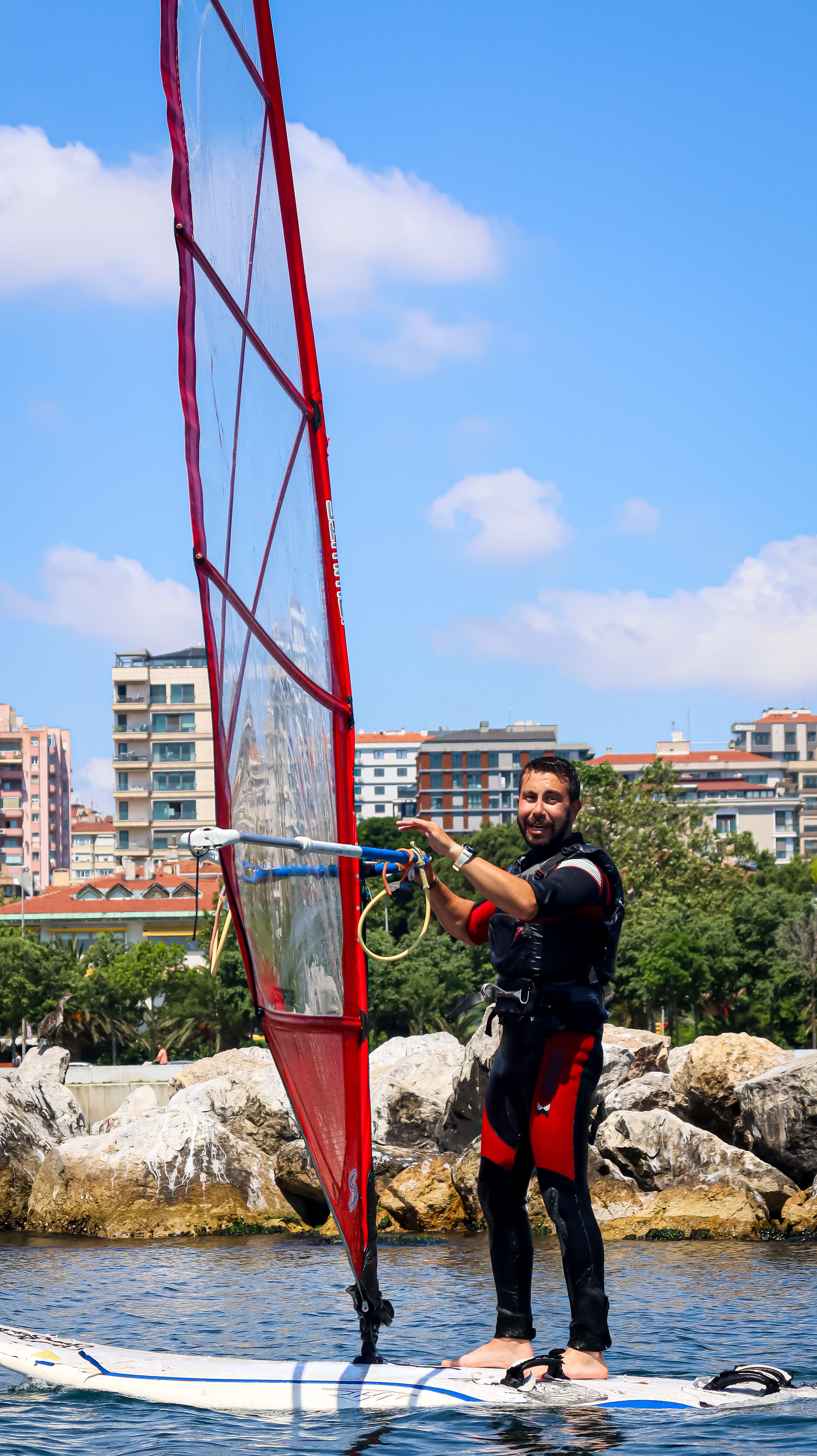 Man Windsurfing on Water near Town · Free Stock Photo