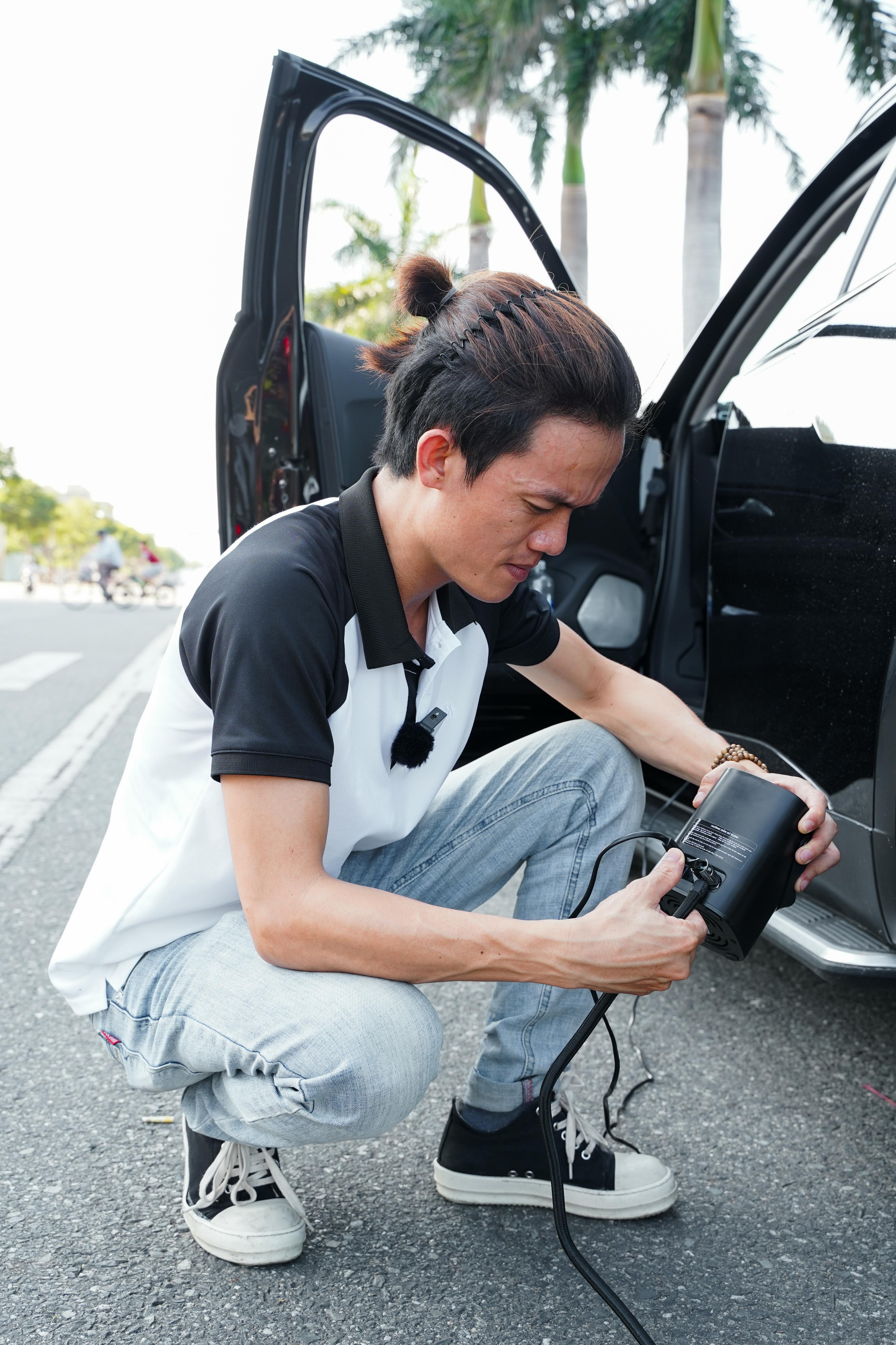 Man Crouching by Car on Street · Free Stock Photo
