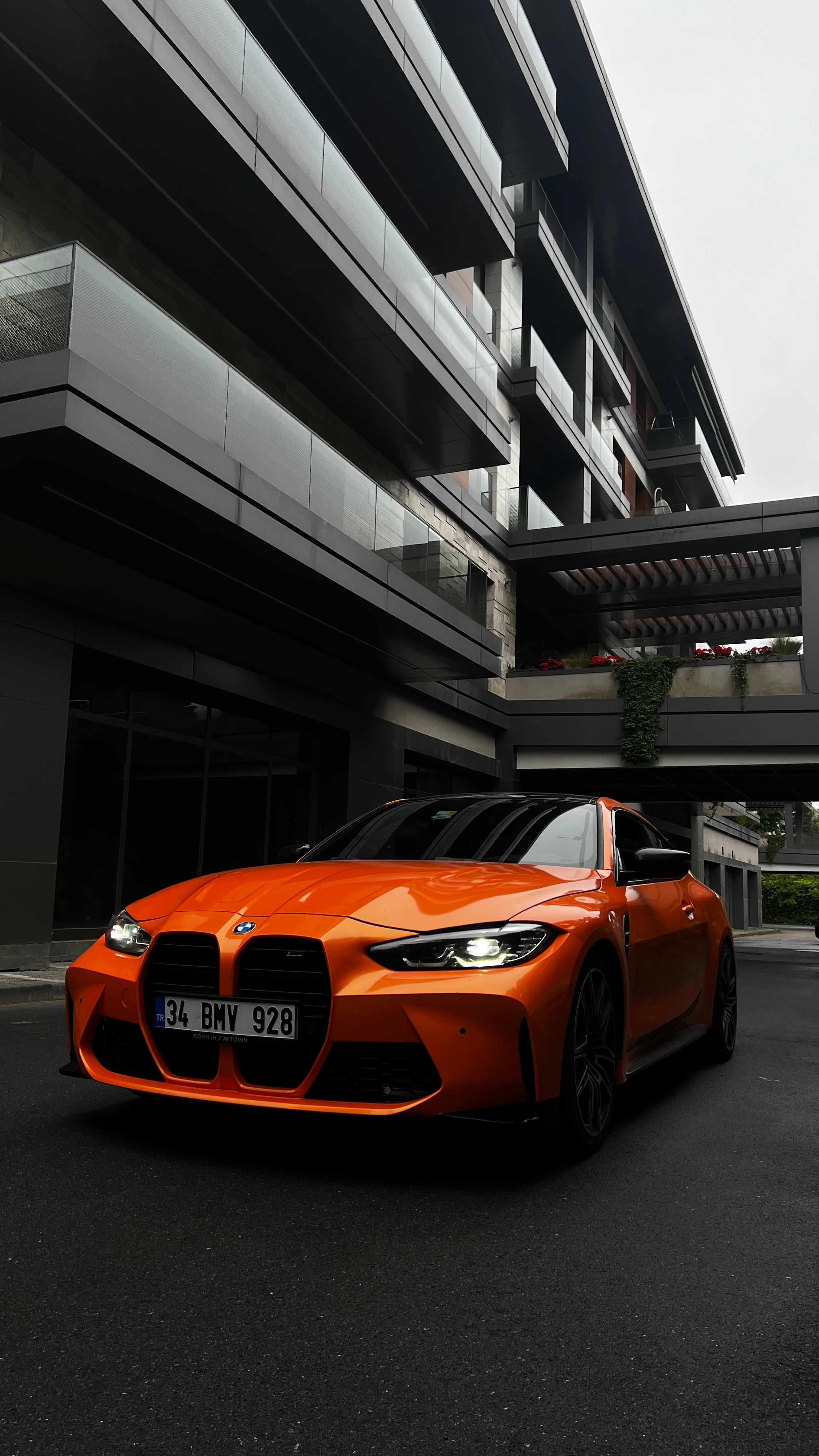 View of an Orange BMW M4 in front of a Modern Building · Free Stock Photo