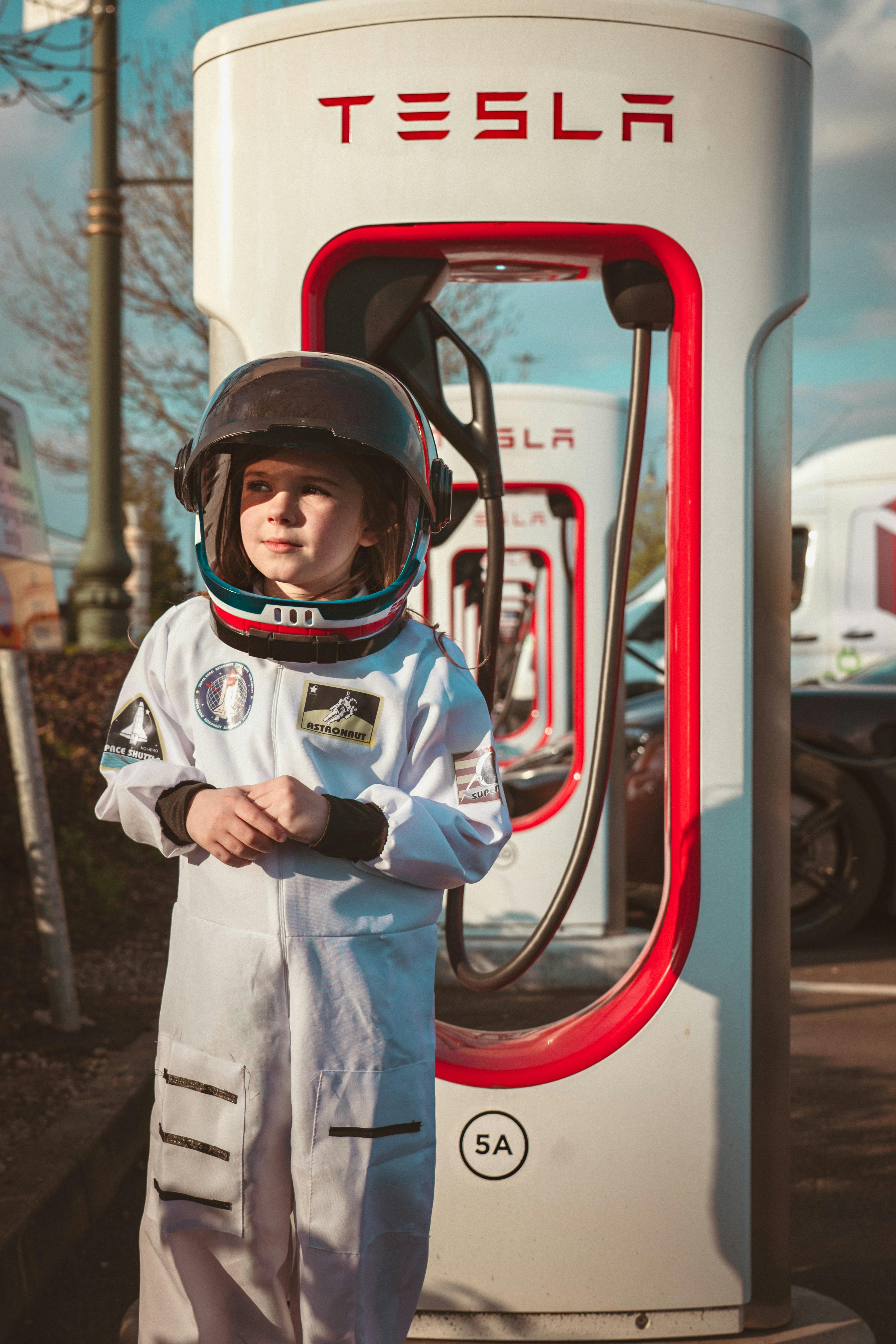 Boy in Helmet Standing by Tesla Charger · Free Stock Photo