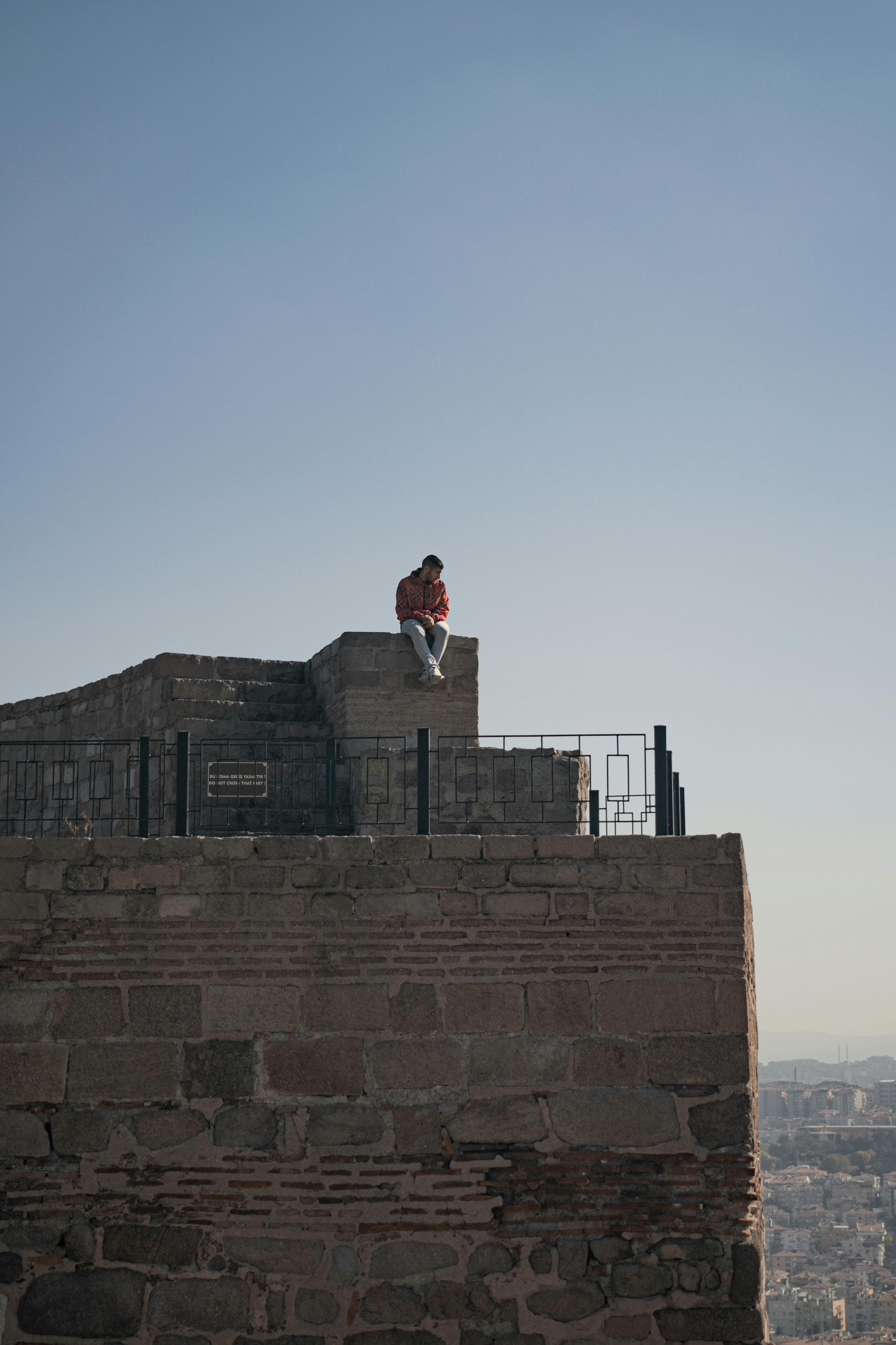 Man Sitting on Building Wall · Free Stock Photo