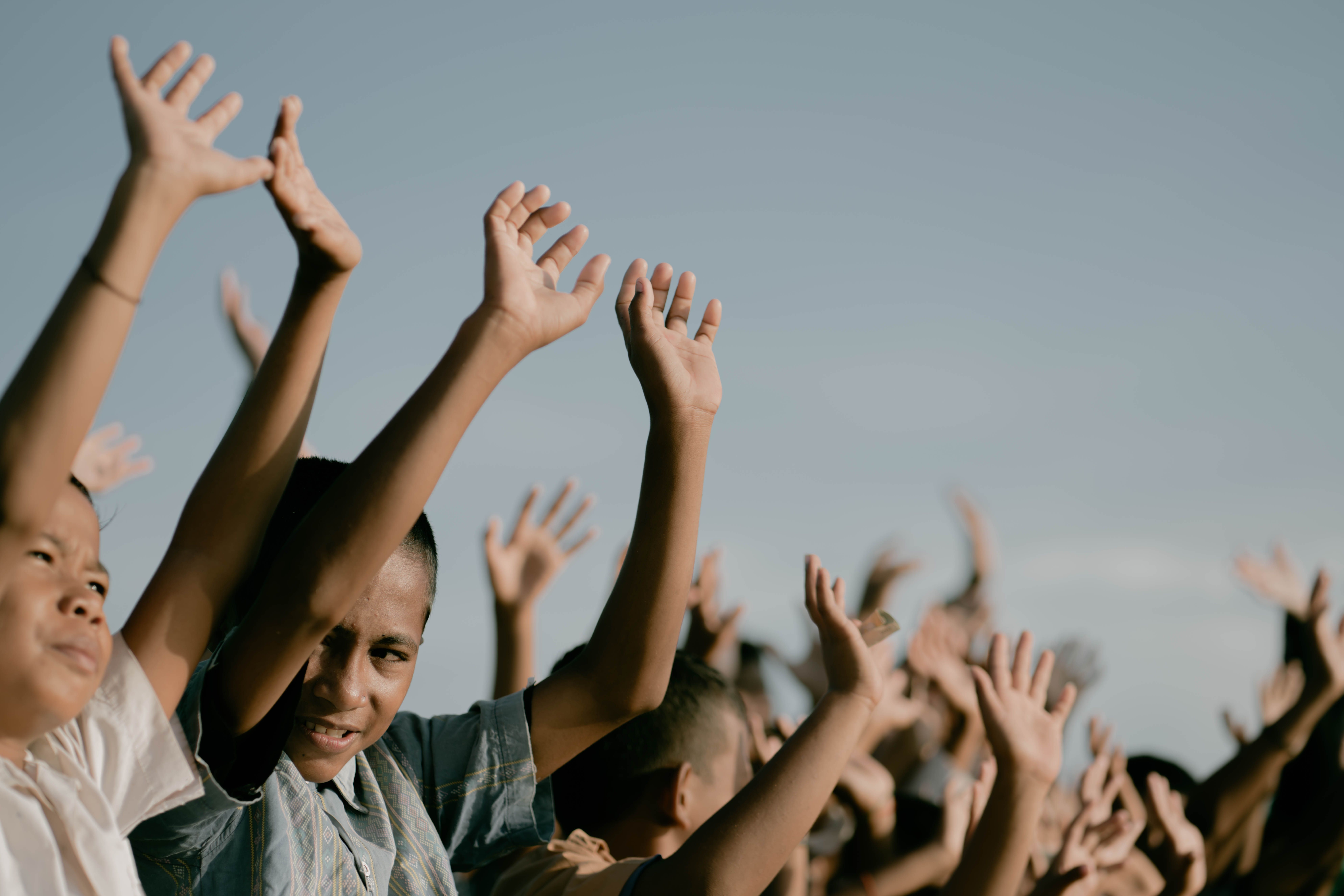 Boys Standing Together with Arms Raised · Free Stock Photo