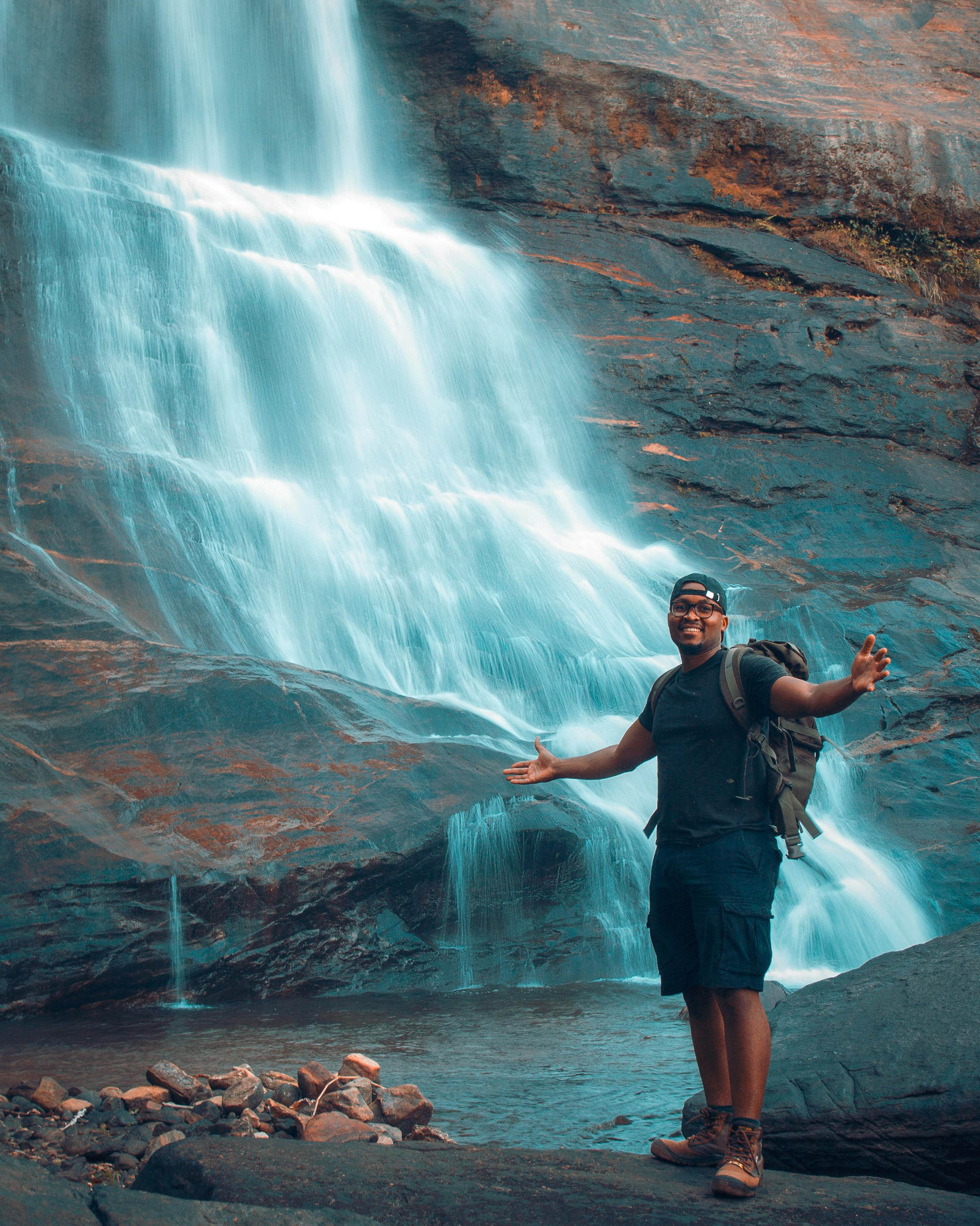 Man Standing on Rock in Front of Waterfalls · Free Stock Photo