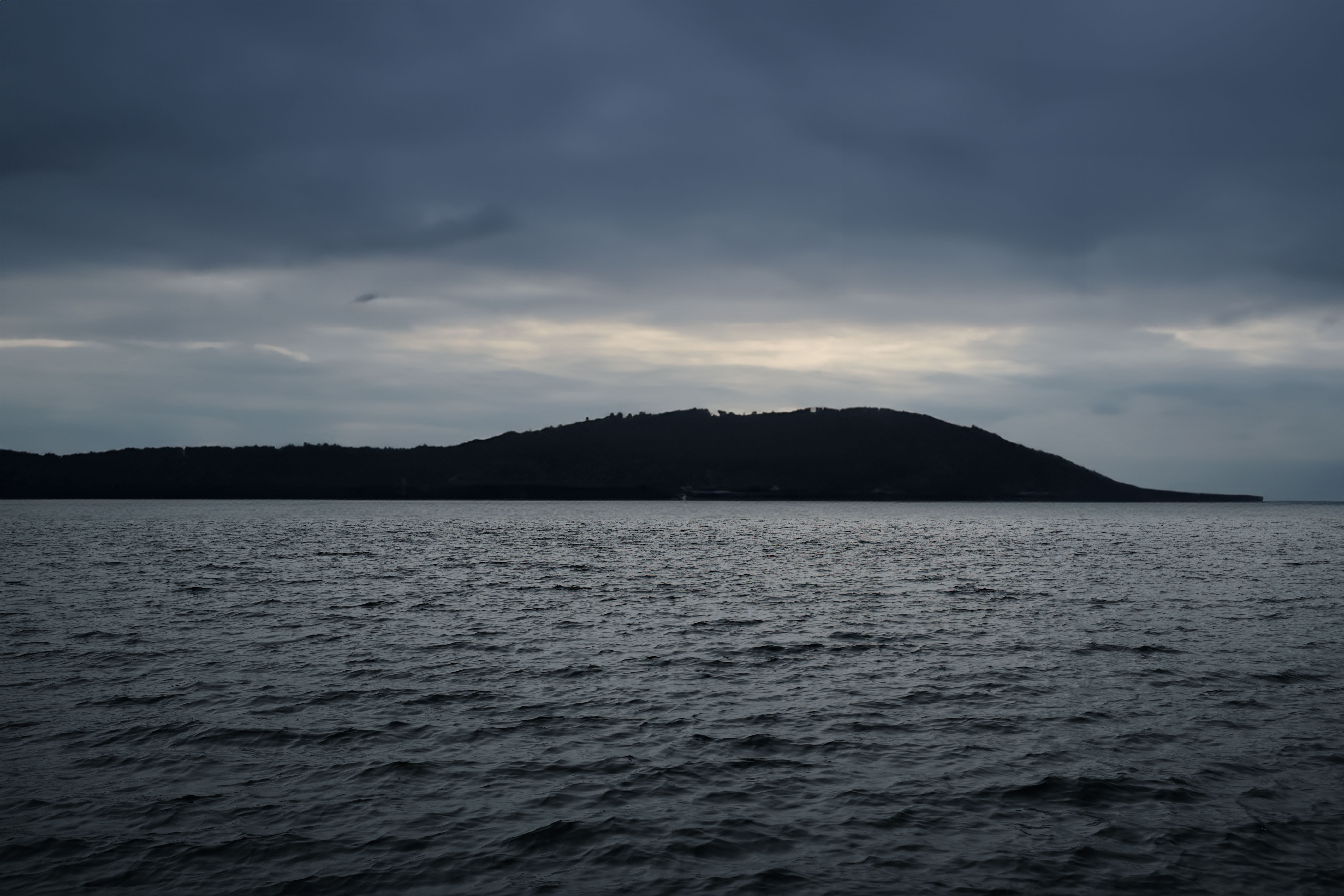 Rain Clouds over Sea Coast with Hill behind · Free Stock Photo