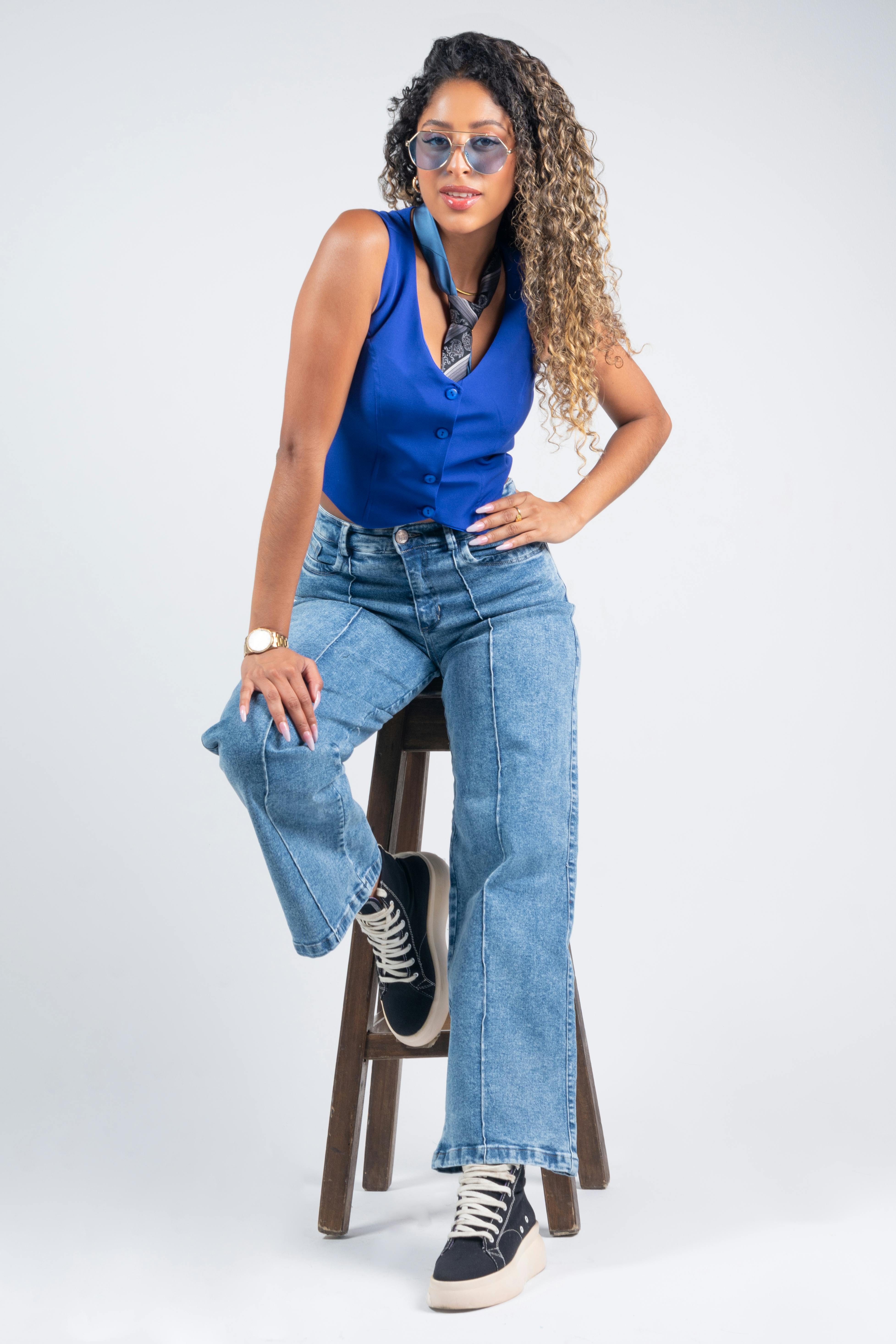 Woman in Blue Tank Top and Jeans Posing on Wooden Stool · Free Stock Photo