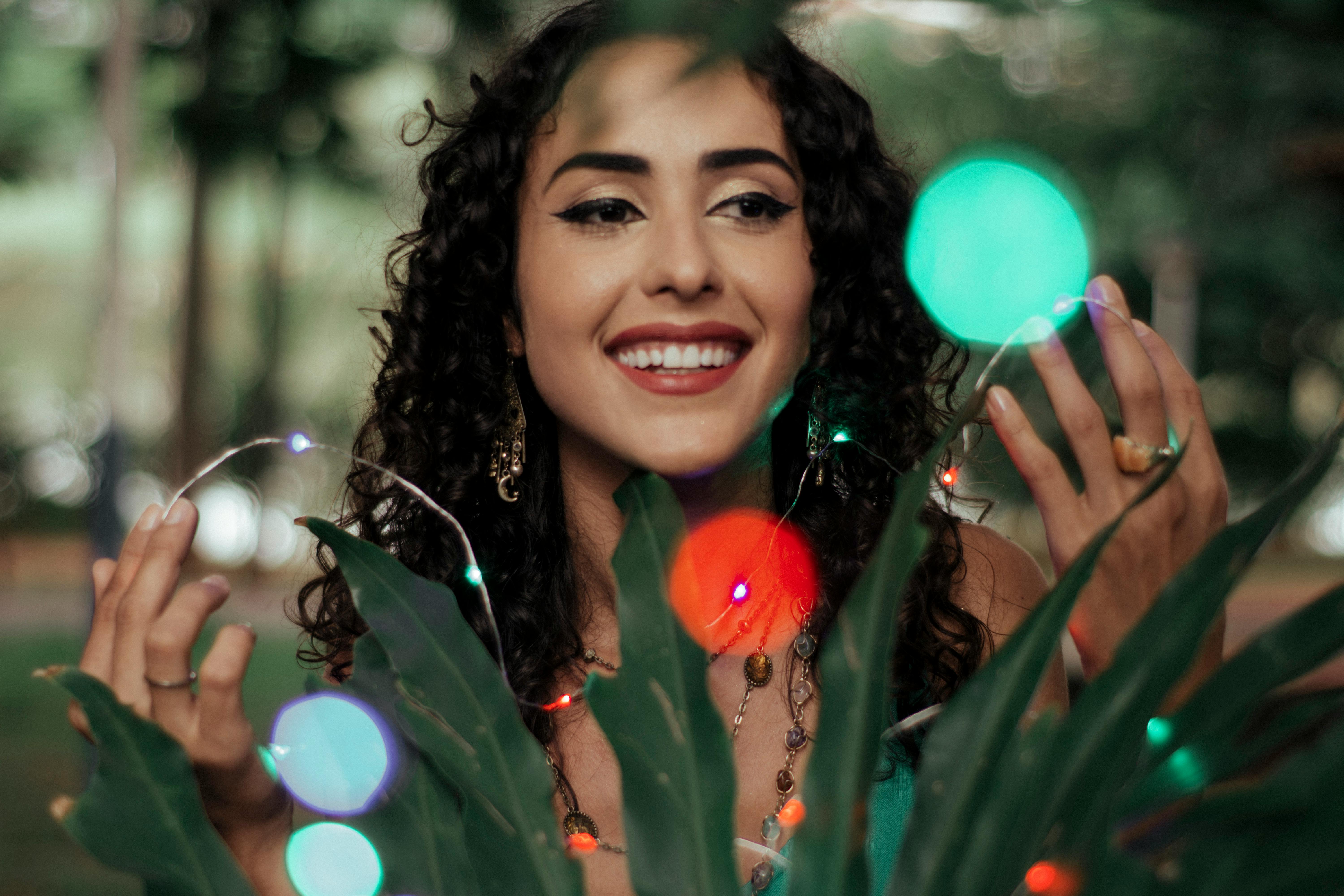 Photo of Woman Smiling While Holding String Lights · Free Stock Photo Photo of Woman Smiling While Holding String Lights · Free Stock Photo