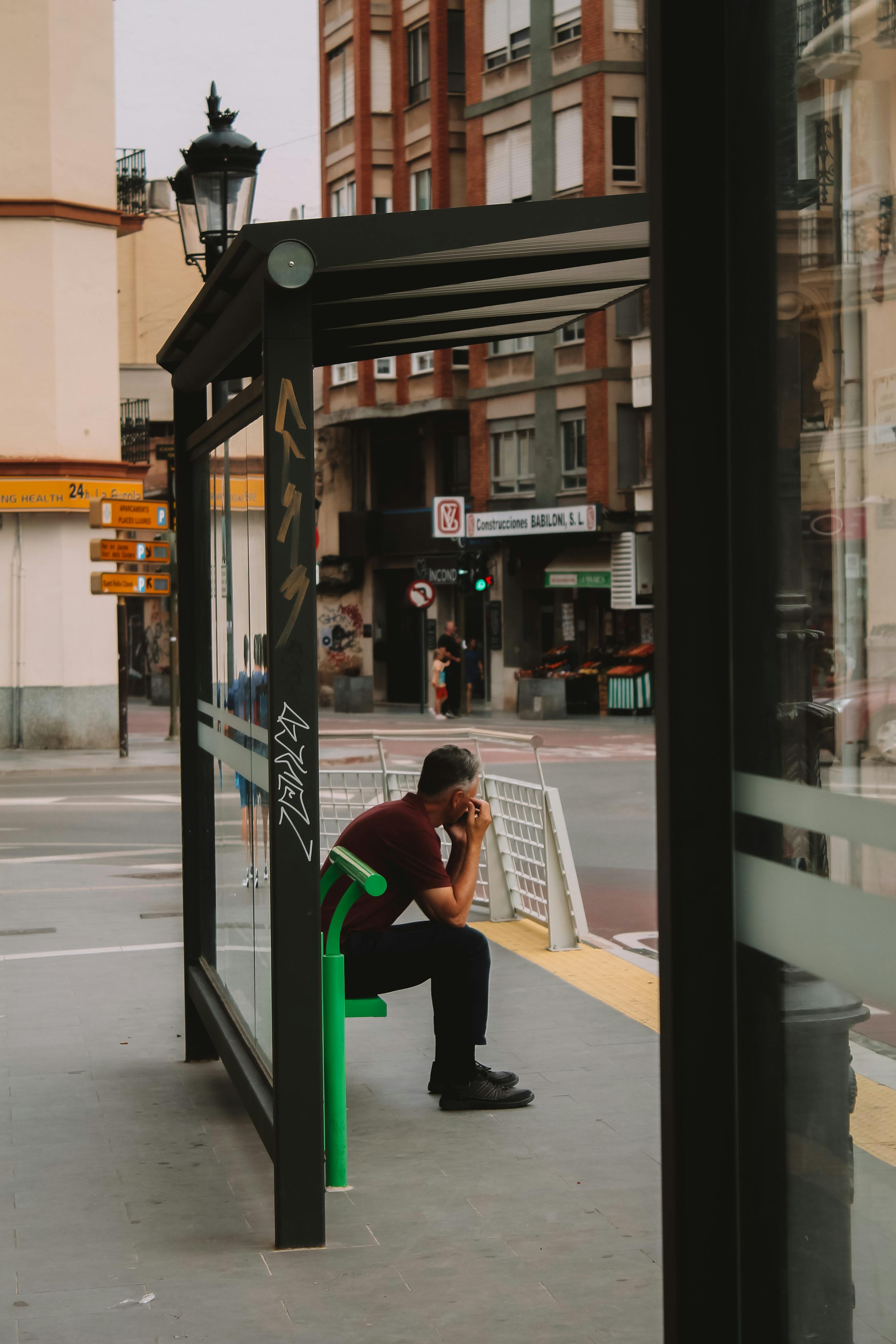 Man Sitting on Bus Stop · Free Stock Photo