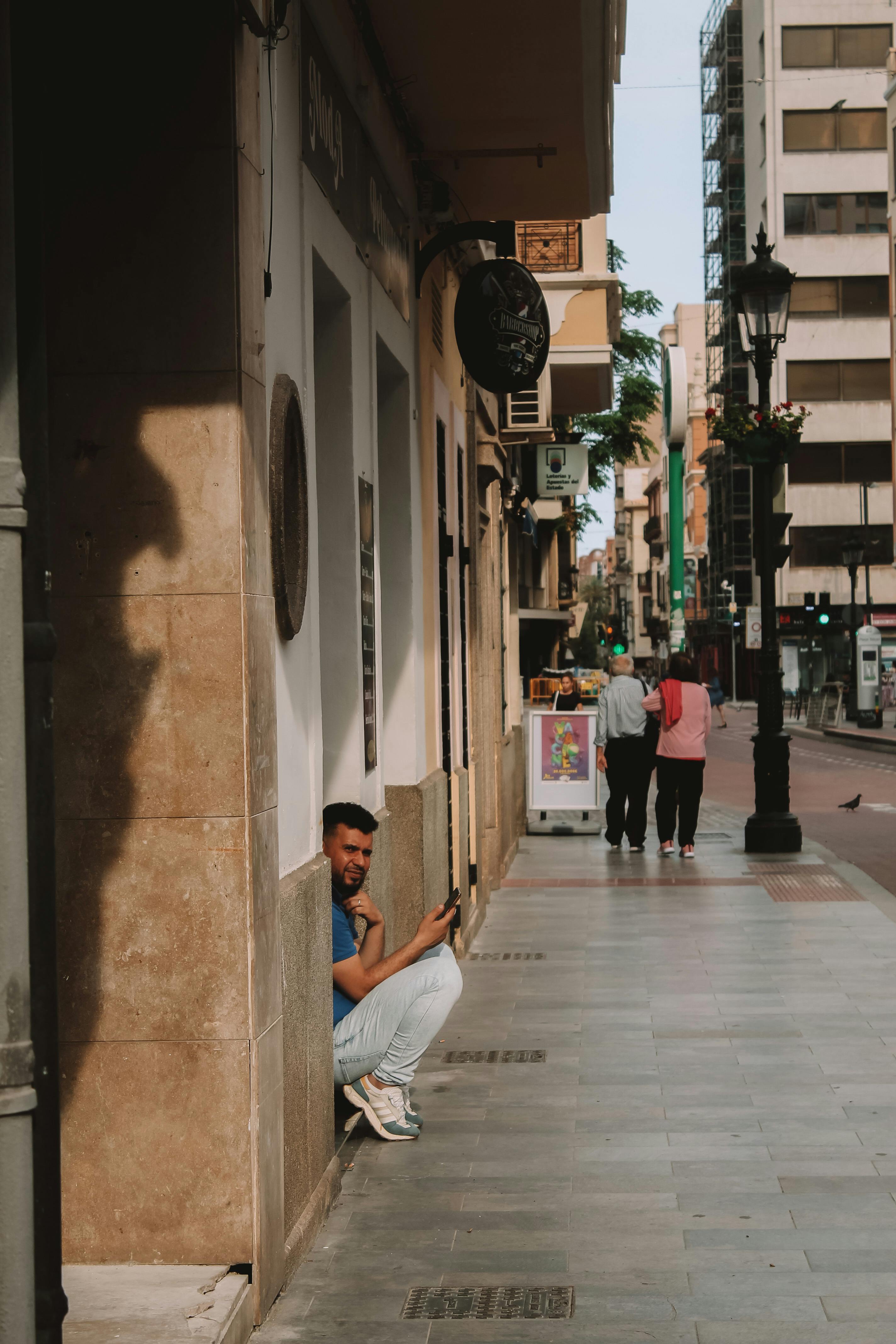 Man Sitting on a Window Parapet with a Smart Phone and Watching the ...