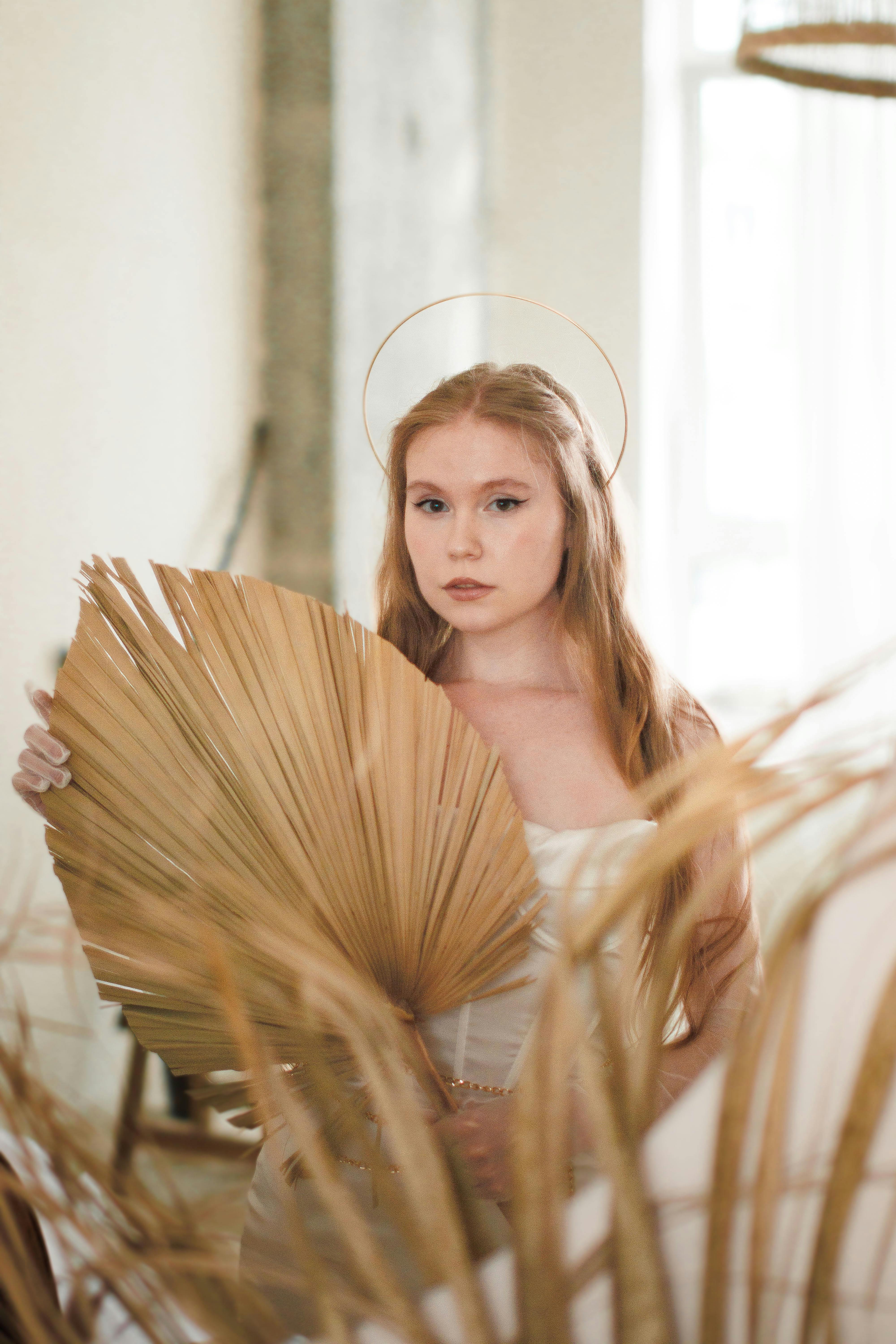 Woman Wearing Halo Crown Holding Large Palm Leaves · Free Stock Photo