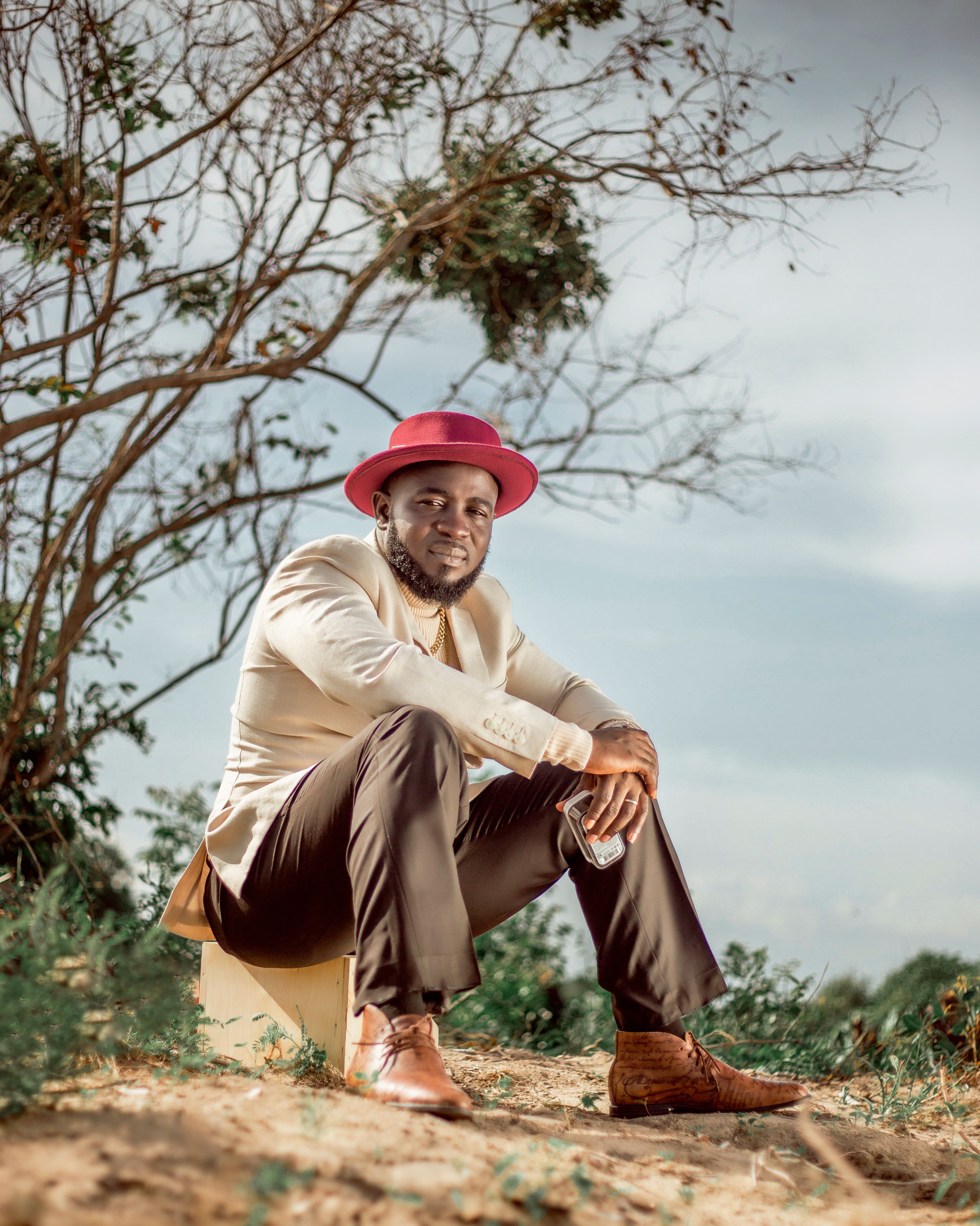 Man Wearing Red Hat Sitting on Stool on Hill Top · Free Stock Photo
