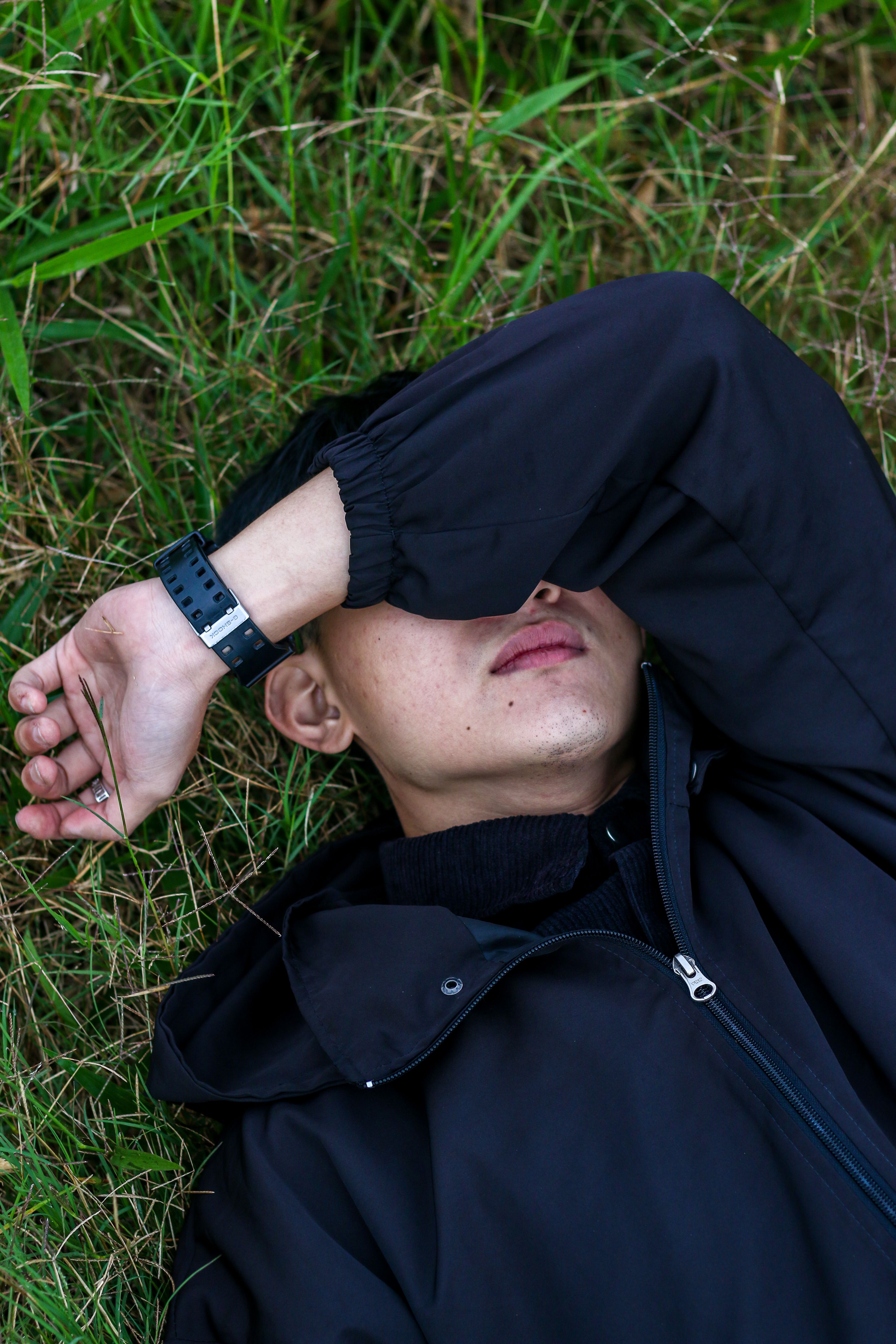 Young Man Lying on the Grass Field and Holding His Arm over His Eyes ...