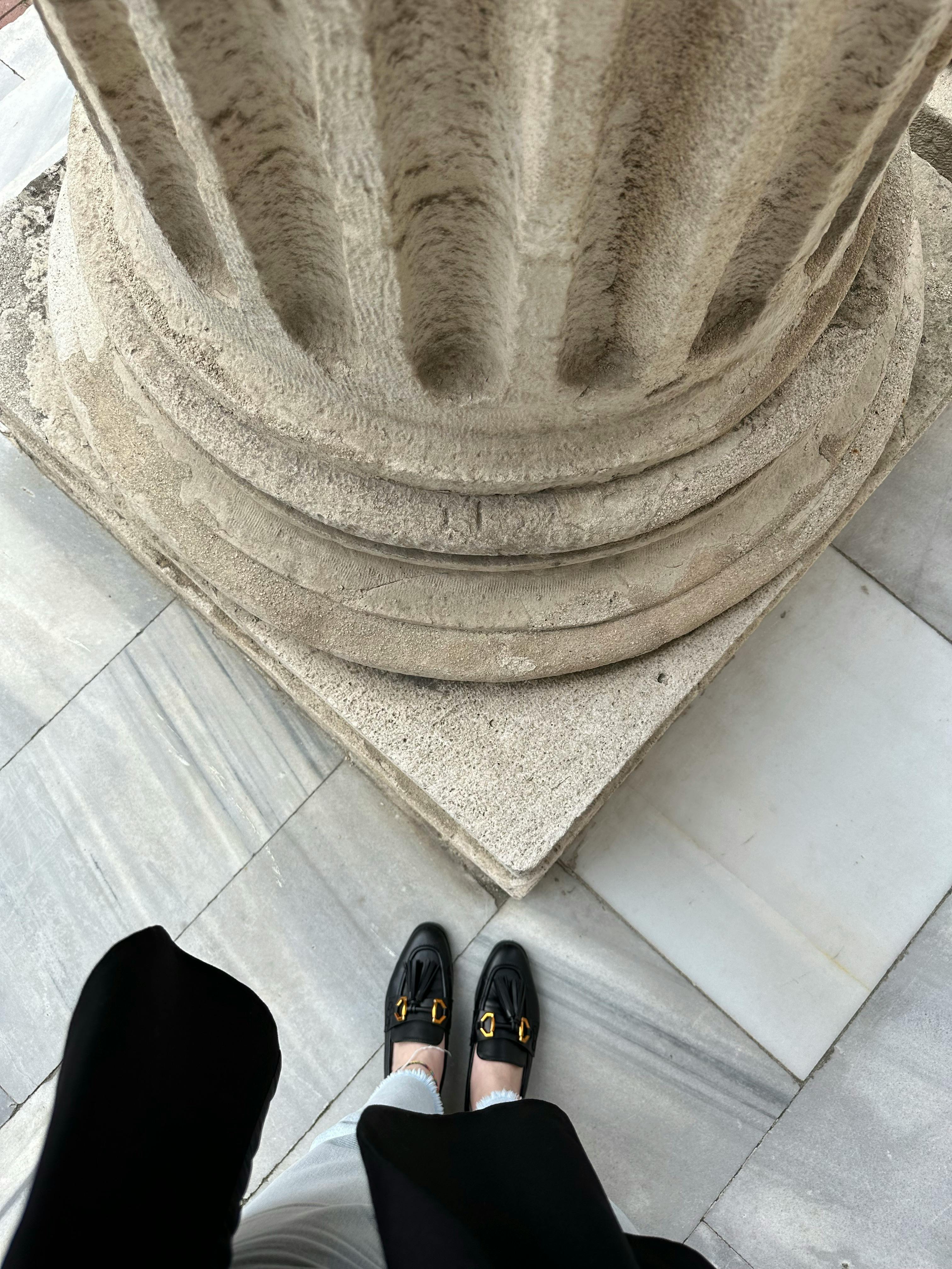 A person standing in front of a pillar with shoes · Free Stock Photo