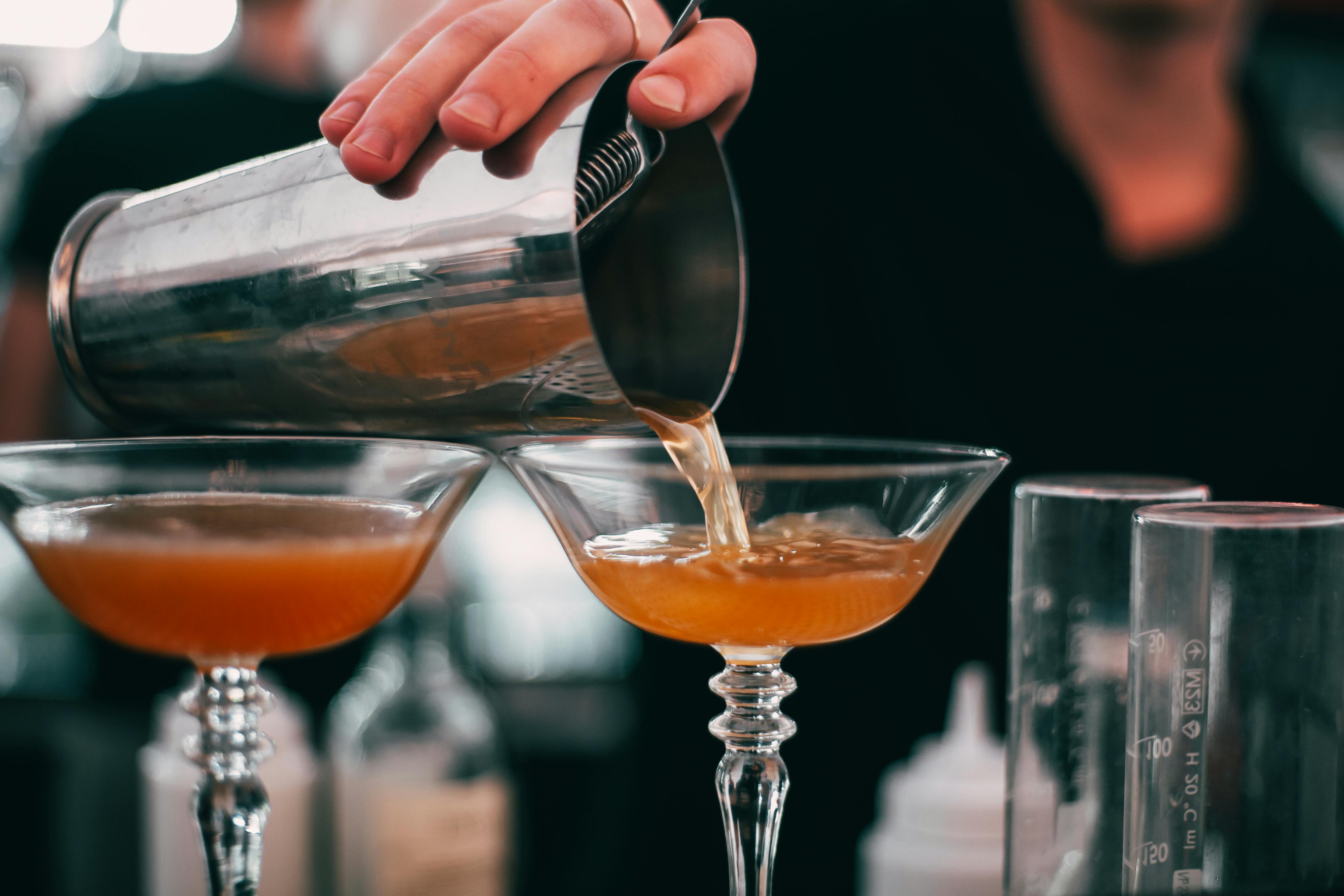 Close-up of hand pouring drink from cocktail shaker into glass · Free ...