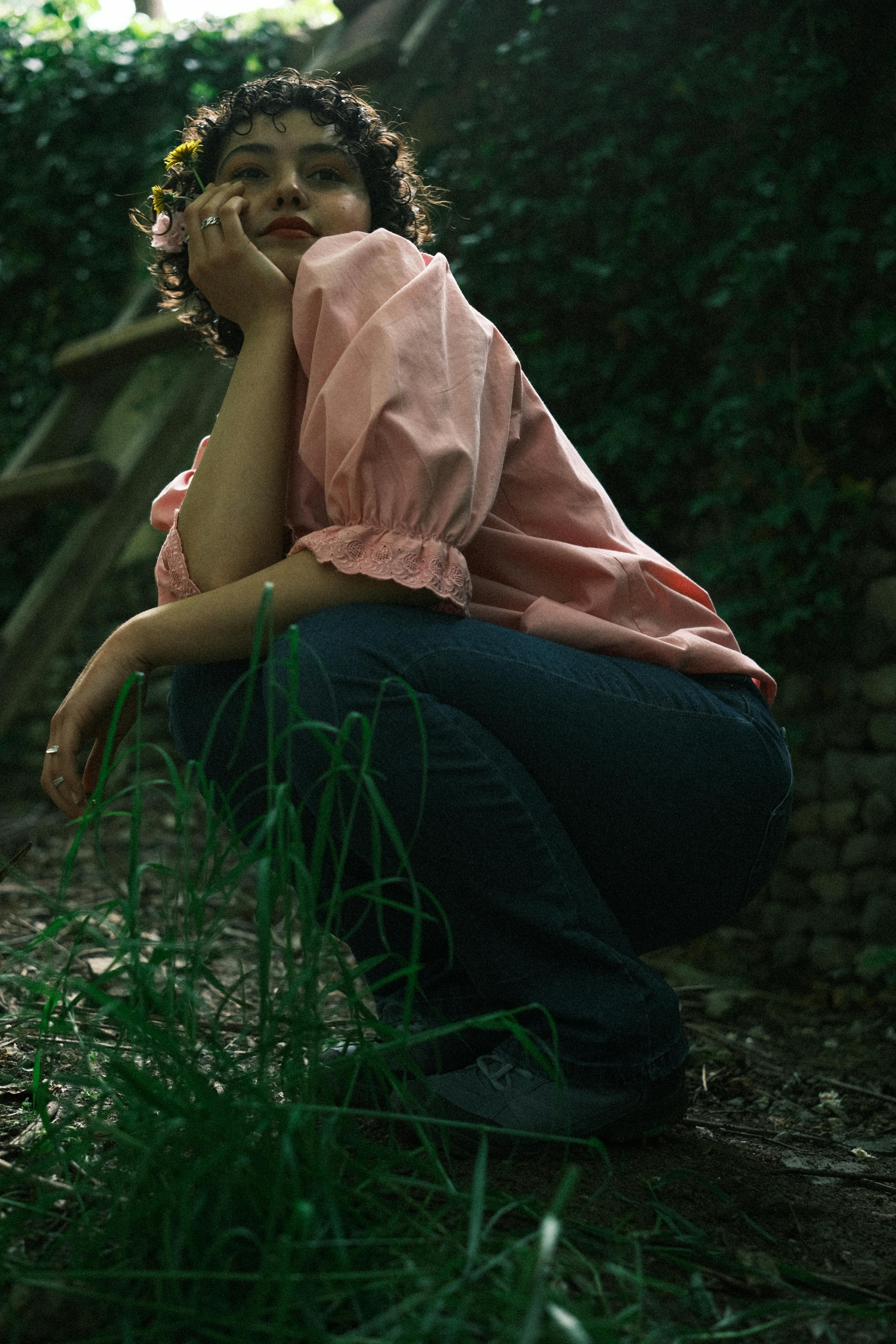 Portrait of Curly Haired Woman in Jeans Crouching · Free Stock Photo
