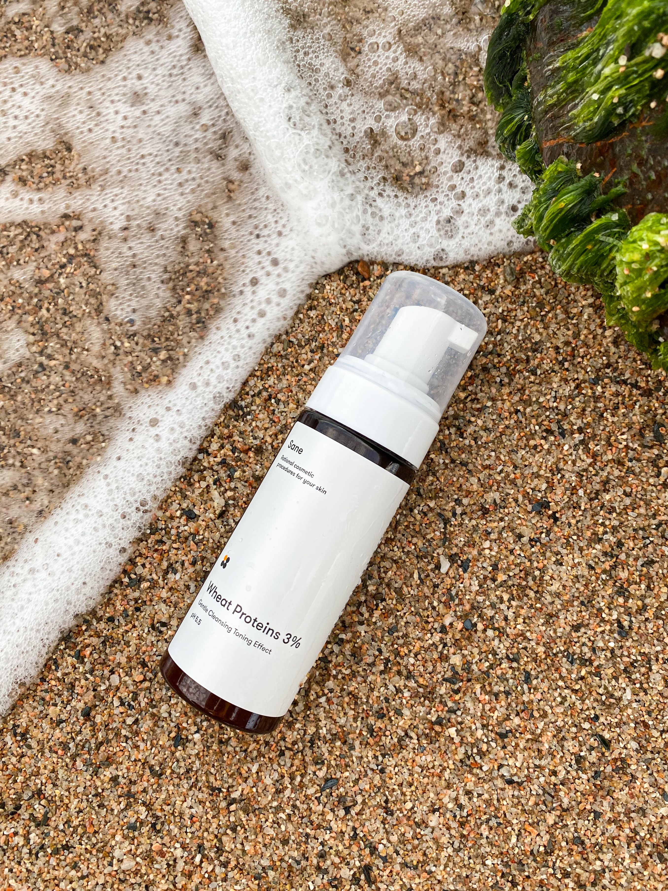 Bottle of Face Cream Lying on Sand by Lake Shore · Free Stock Photo