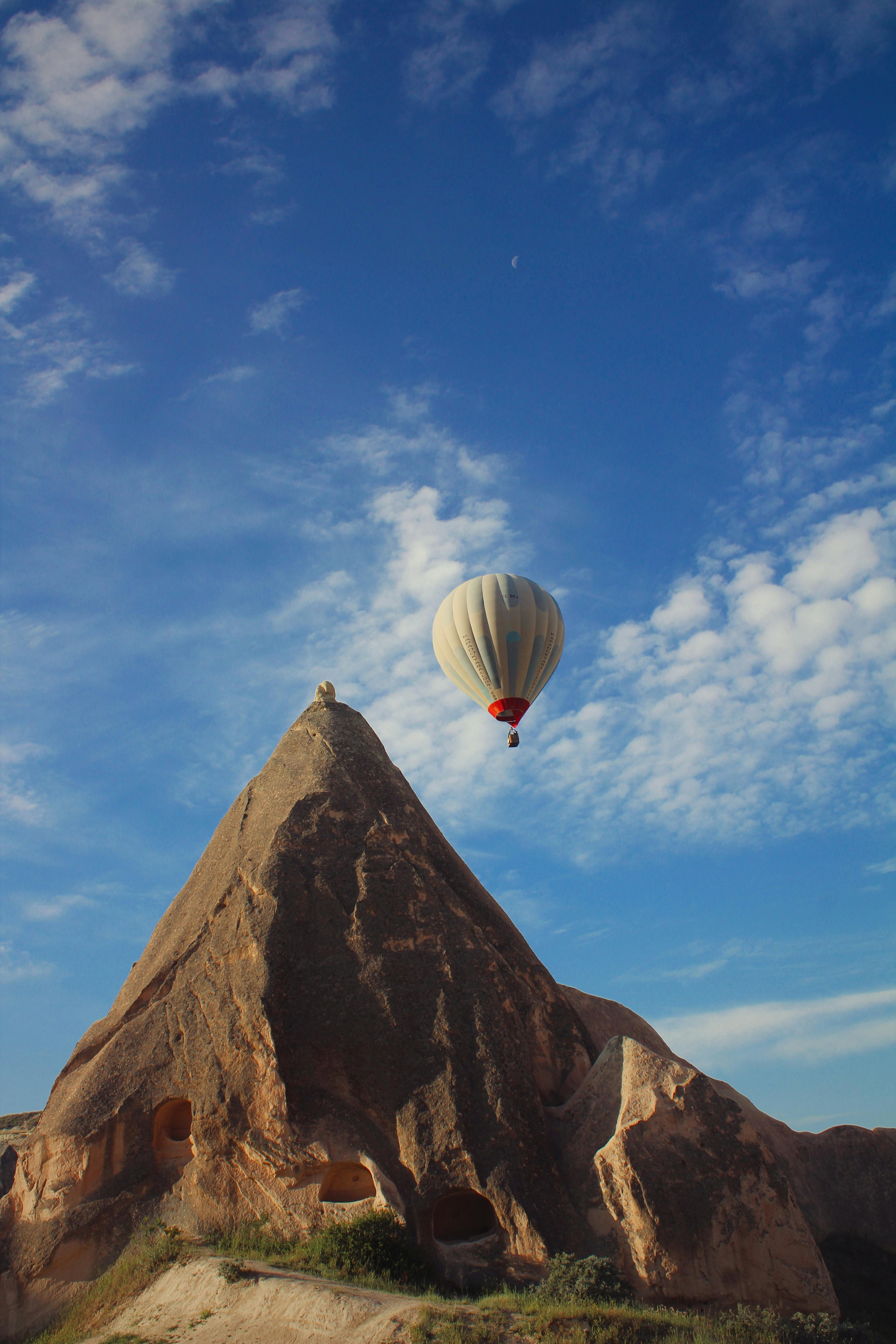 Multicolored air balloons flying over cliffs and parked retro van ...