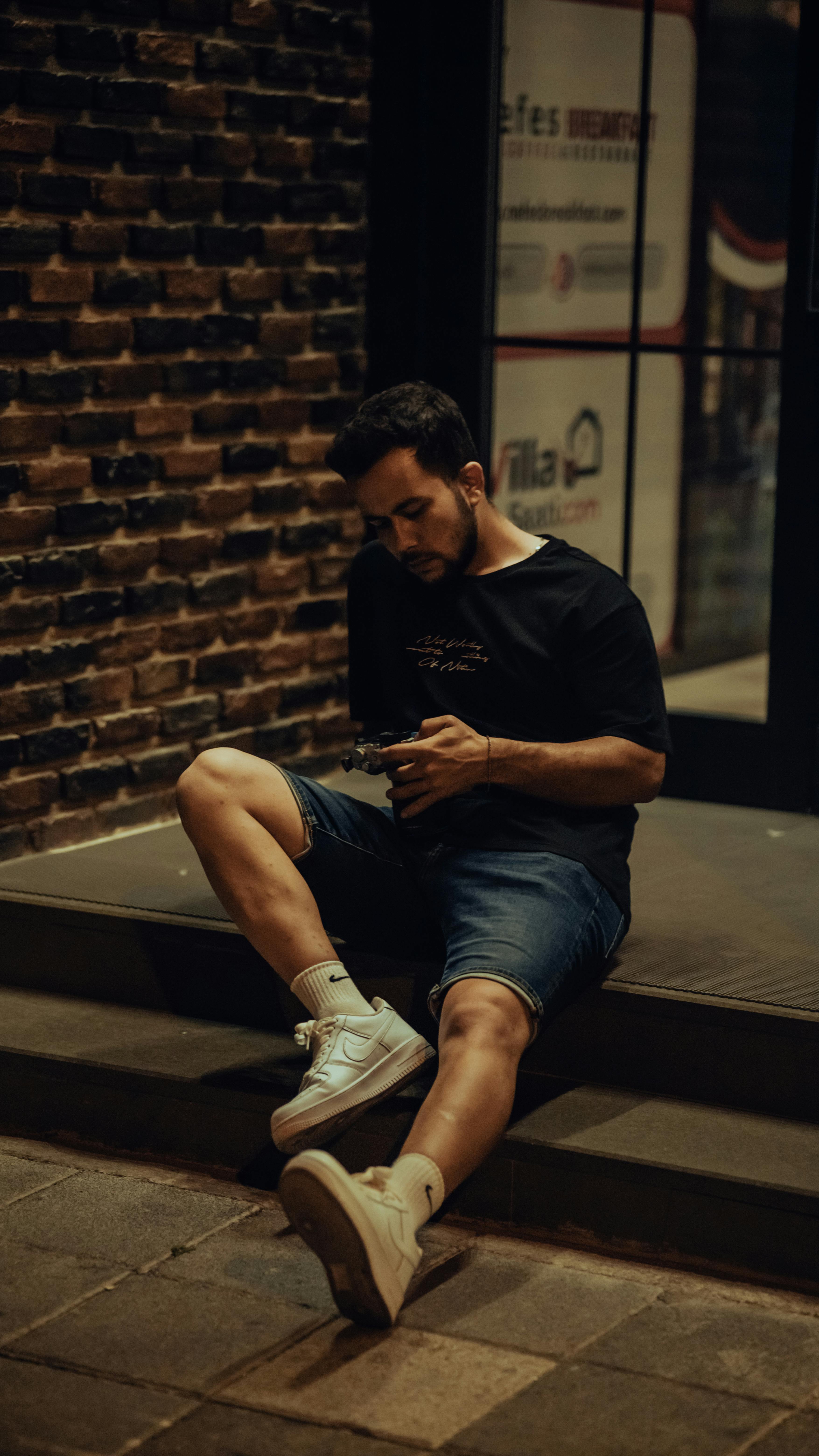 Man Sitting on Step by Glass Door · Free Stock Photo