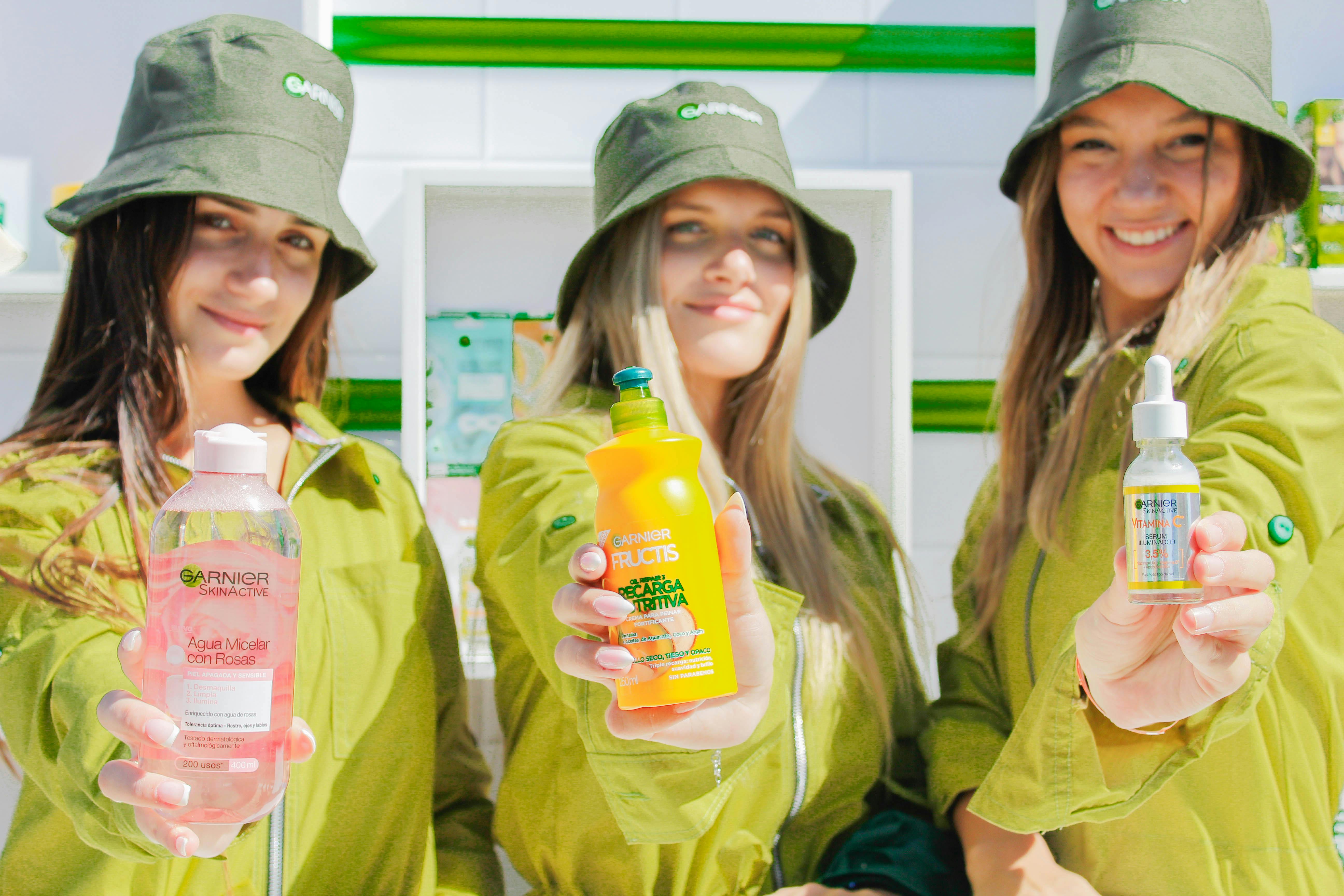 Young Women in Yellow Jackets and Green Bucket Hats Presenting Bottles ...