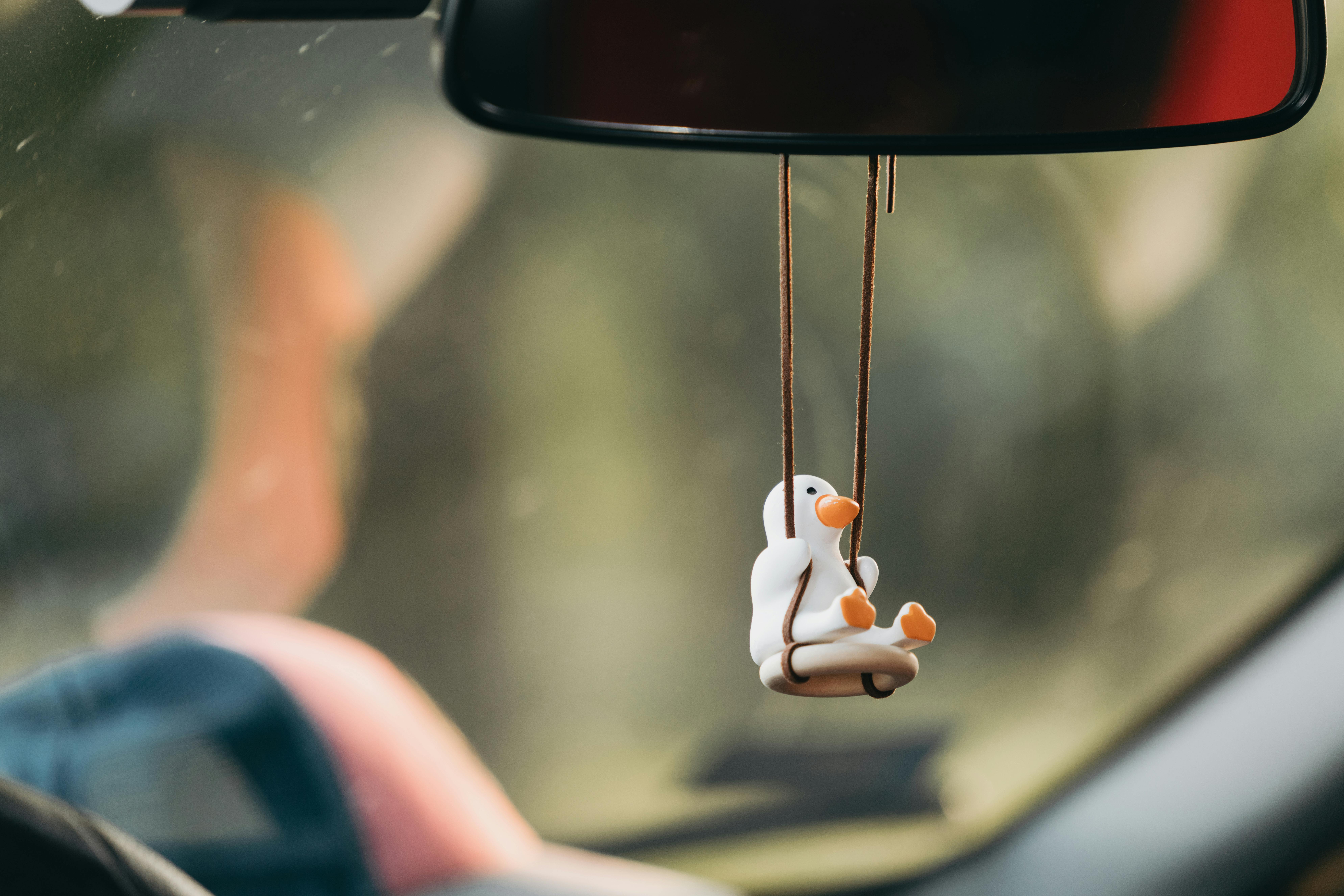 White Swinging Duck Figurine Hanging on a Rear-View Mirror of a Car ...