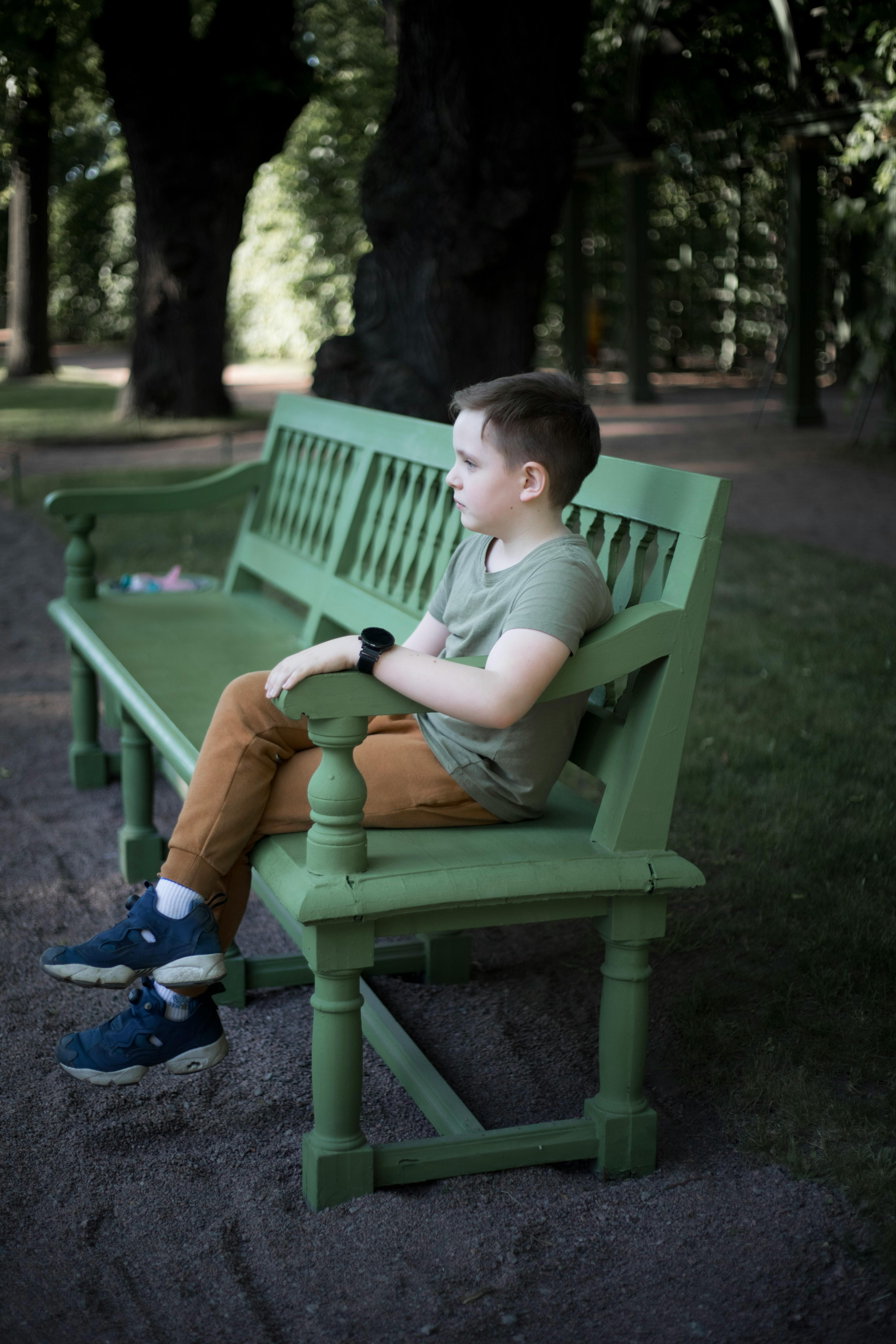 Boy Sitting on Green Bench · Free Stock Photo