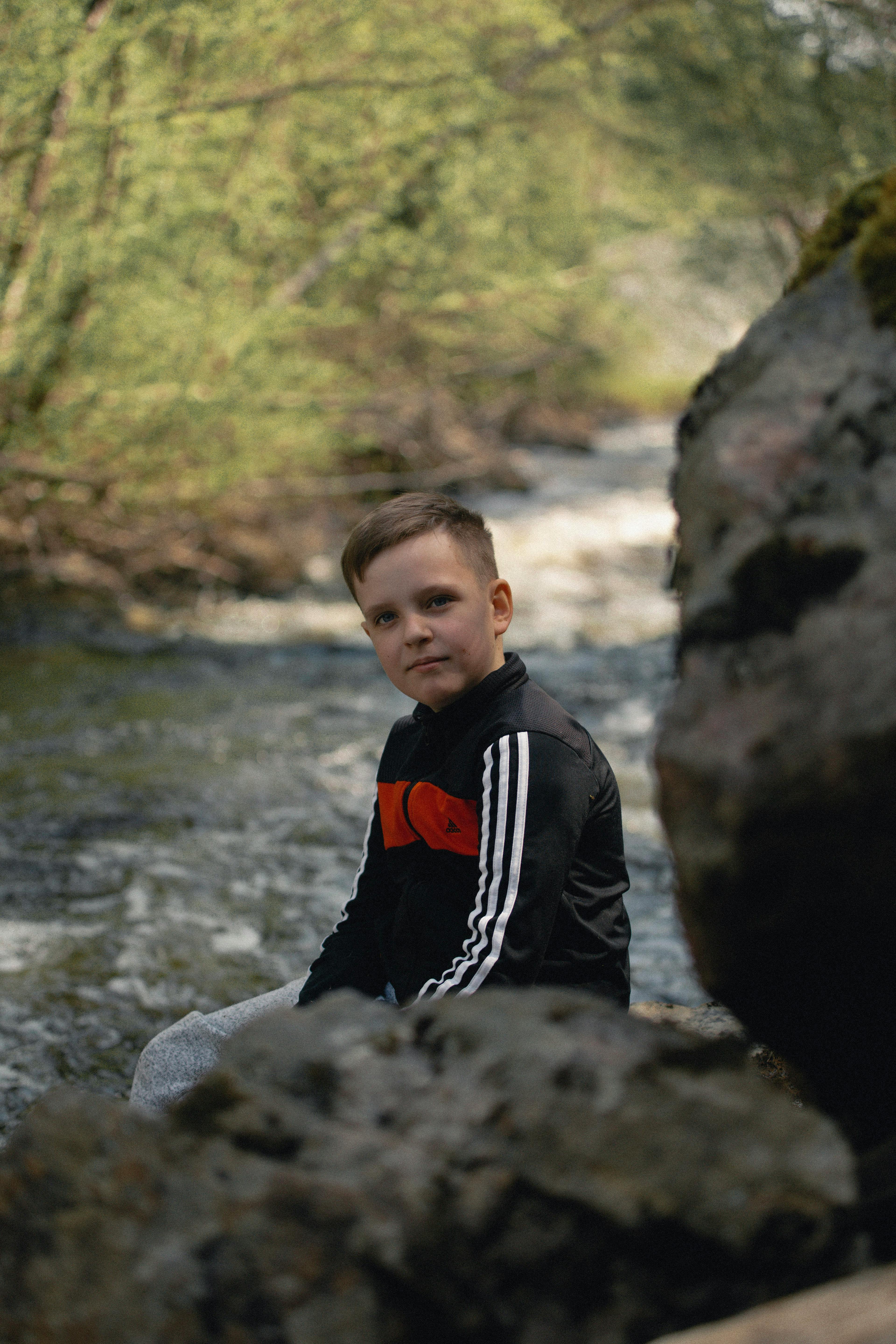 Boy Sitting on Stone by the River · Free Stock Photo