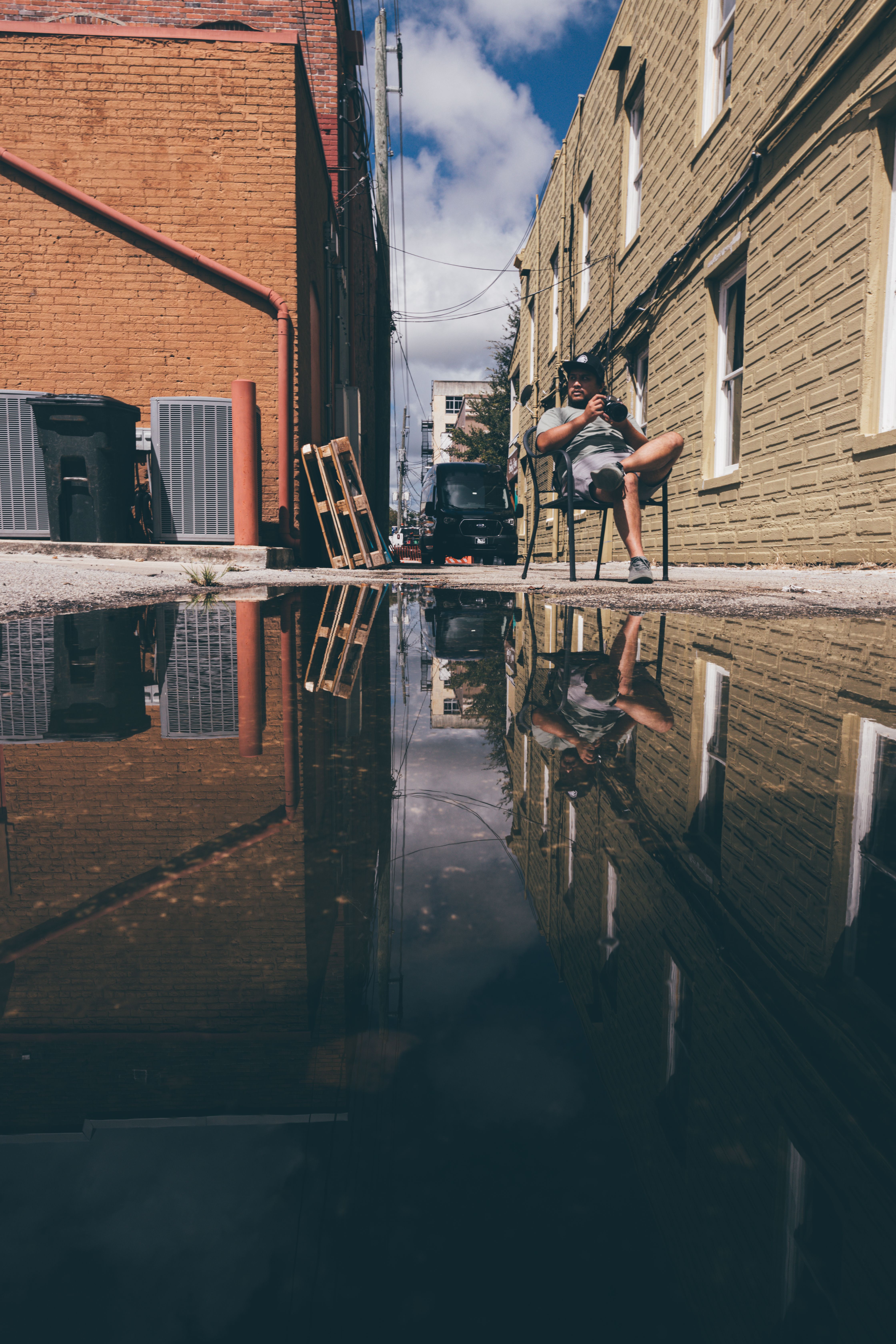 Man Sitting near Puddle on Street · Free Stock Photo