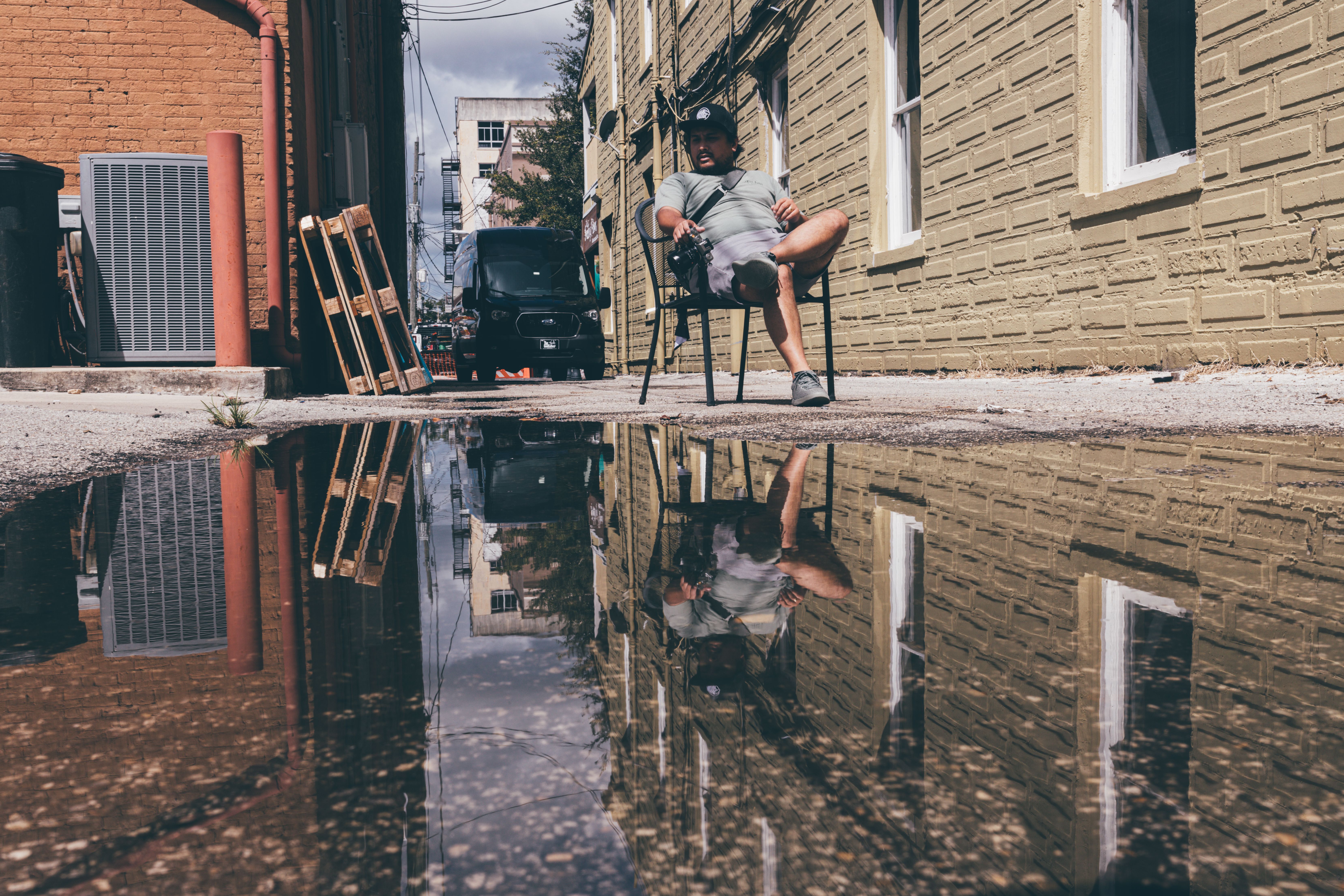 Man Sitting on a Garden Chair in Front of a Puddle on the Street · Free ...
