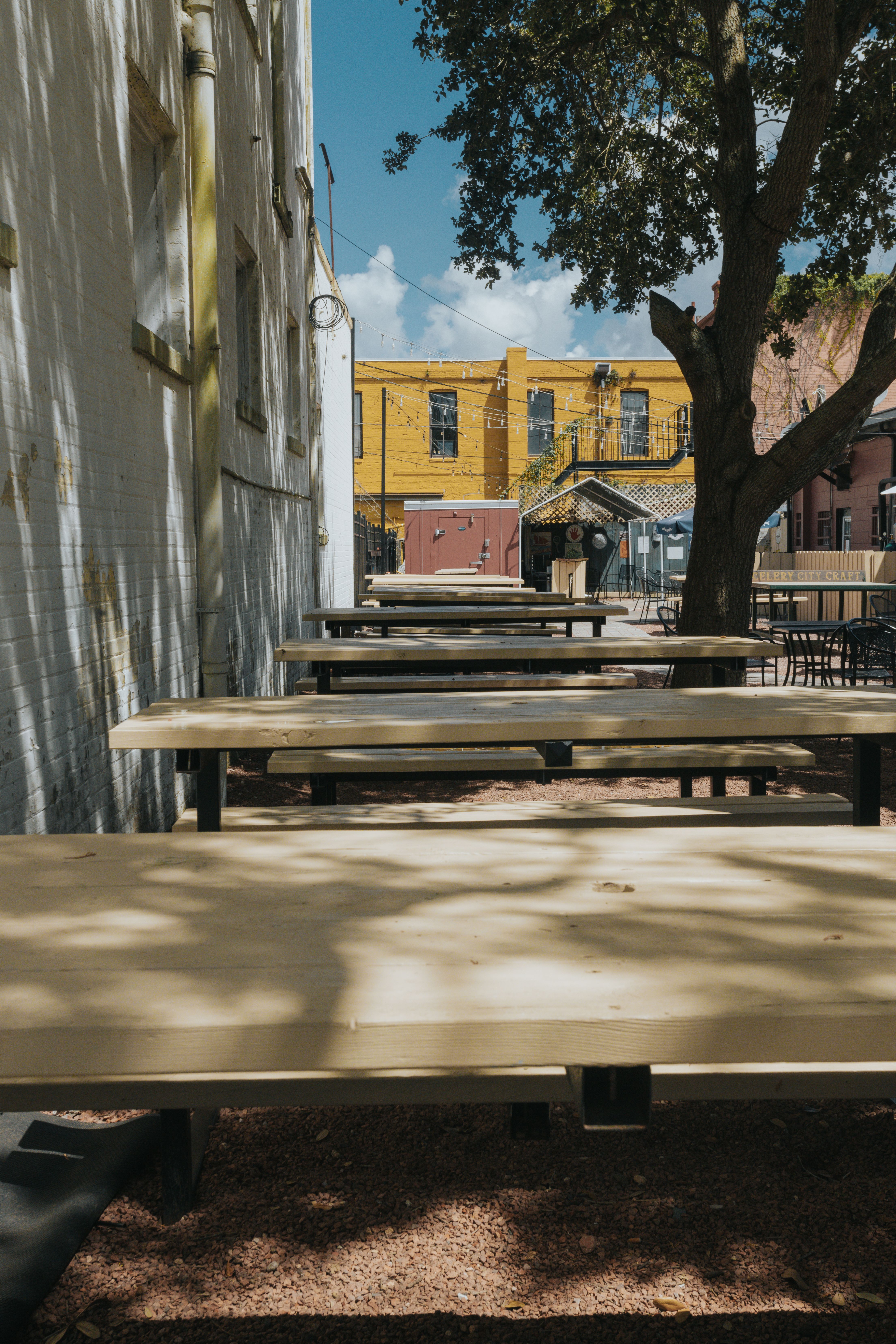 Wooden Tables near Building Wall · Free Stock Photo