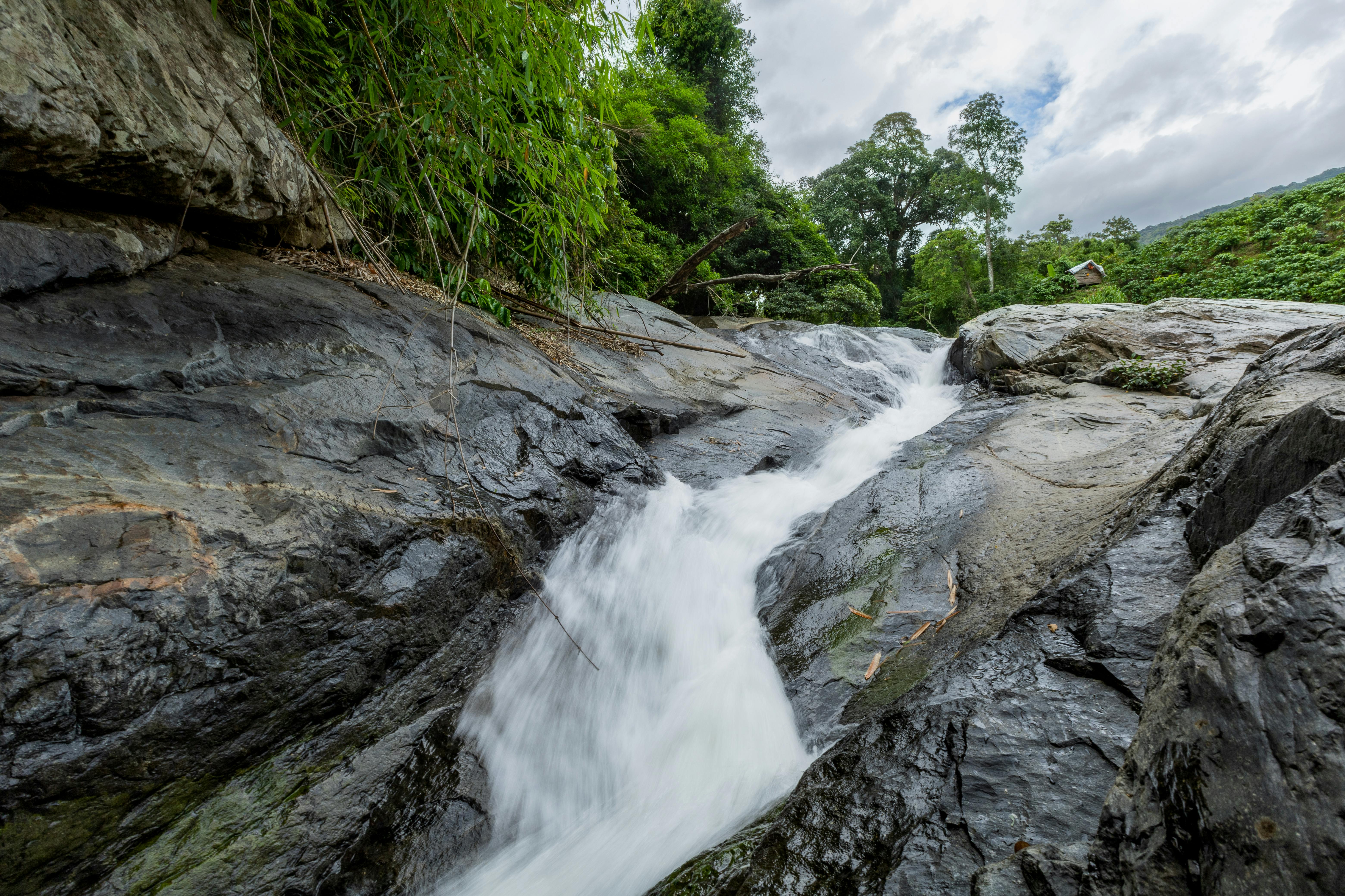 A waterfall flowing over rocks in a forest · Free Stock Photo