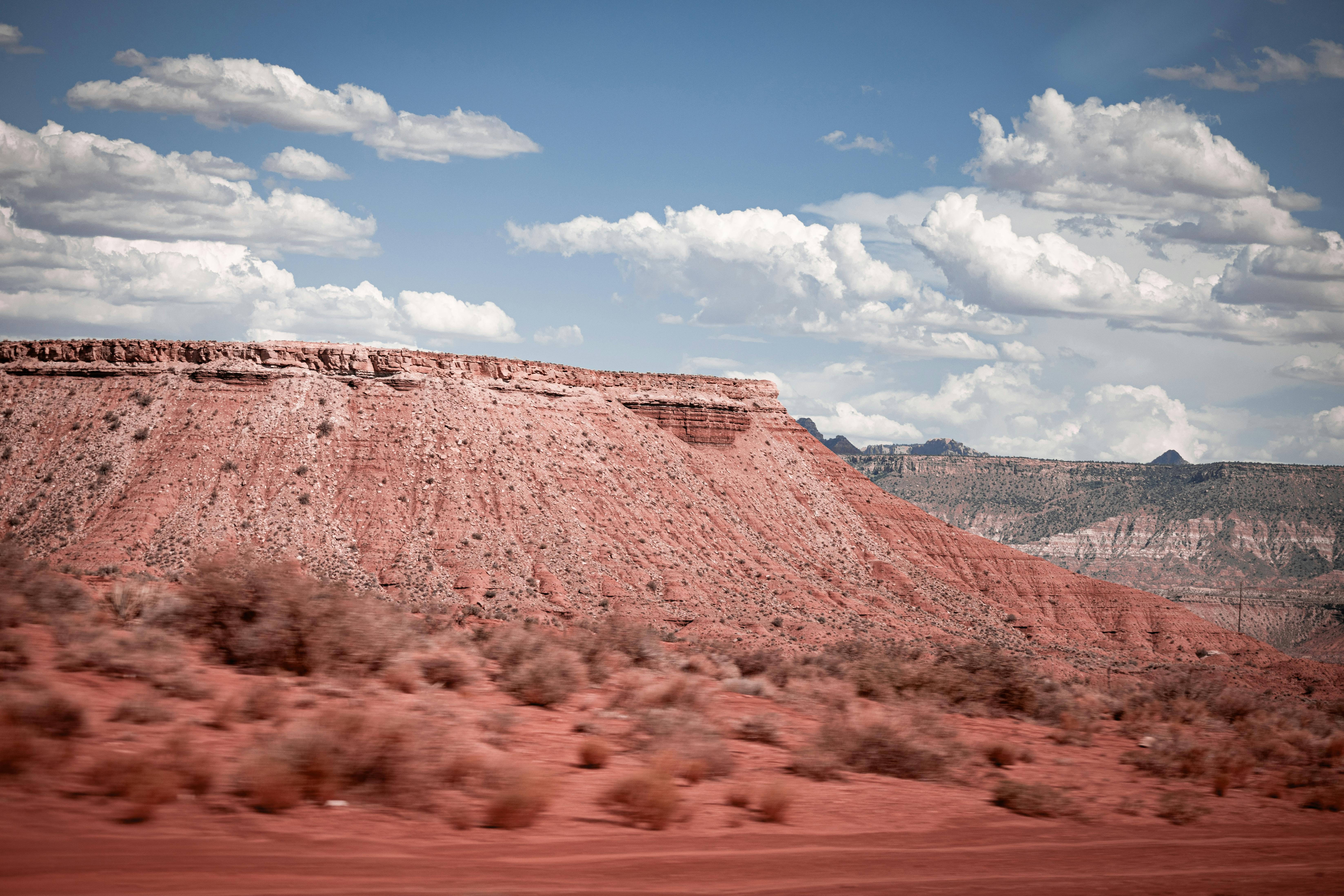 A red desert landscape with clouds and mountains · Free Stock Photo