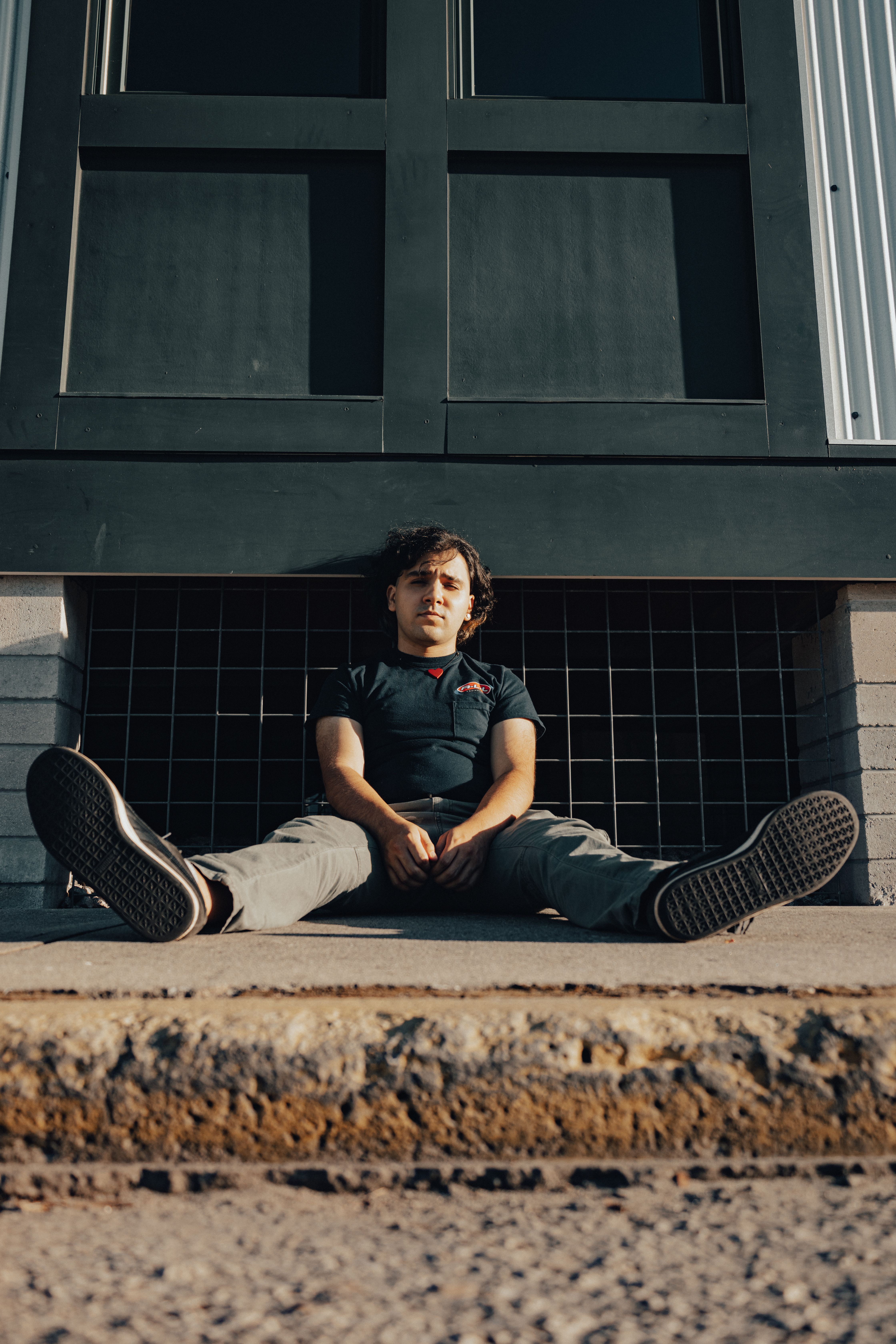 A young man sitting on the ground outside of a building · Free Stock Photo