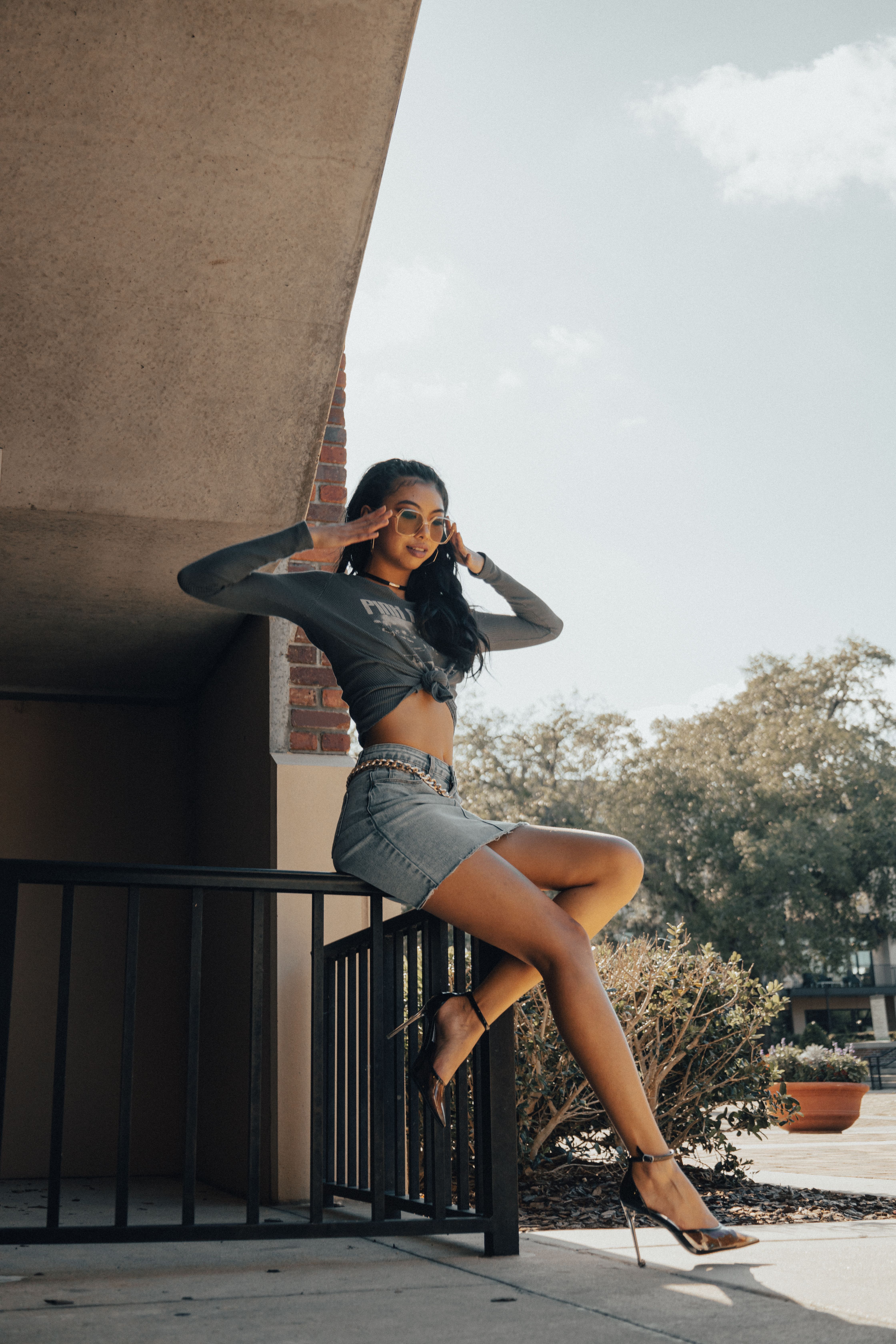A woman in a crop top and shorts is posing on a railing · Free Stock Photo
