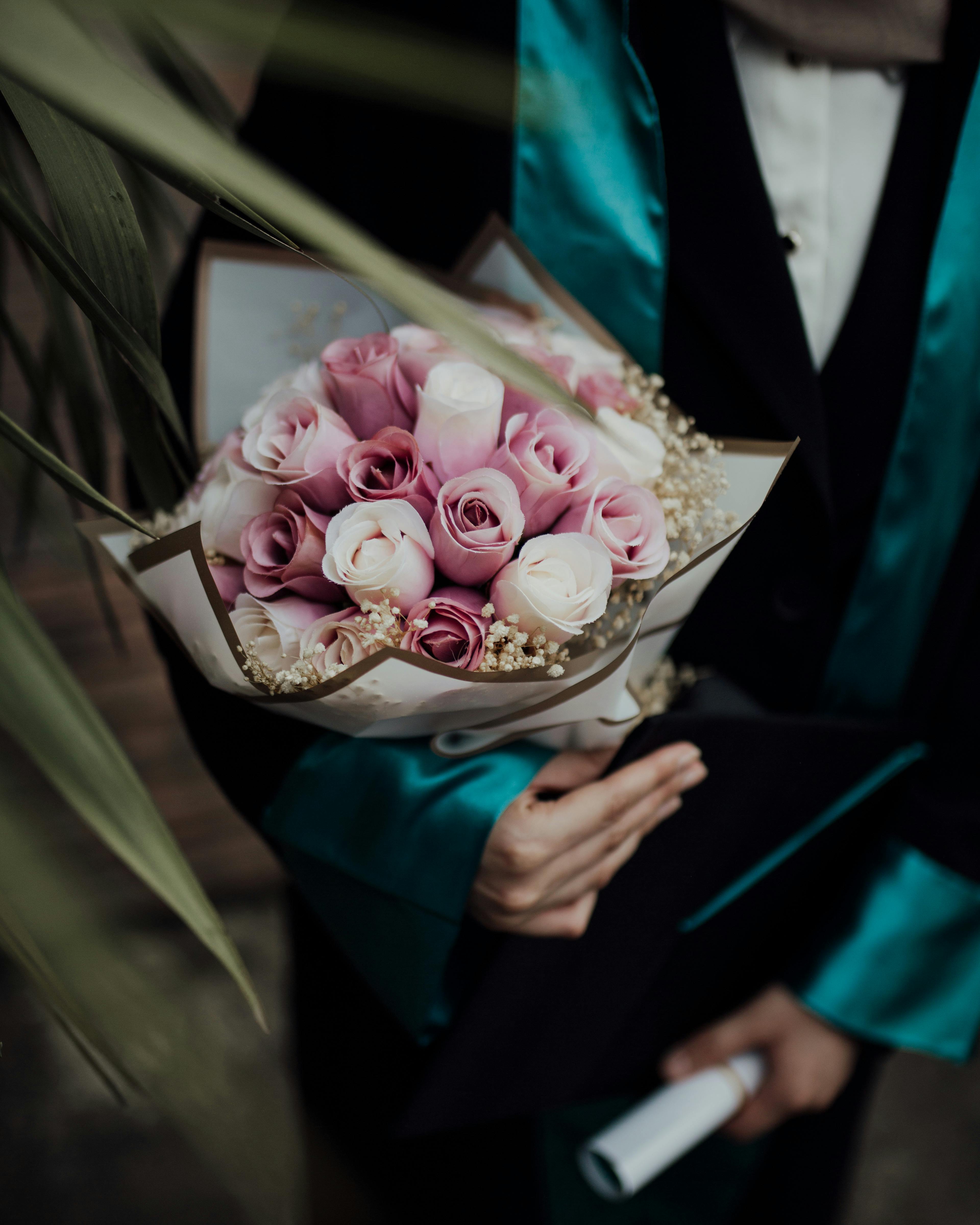 Woman in a Graduation Gown Holding a Bunch of Flowers · Free Stock Photo
