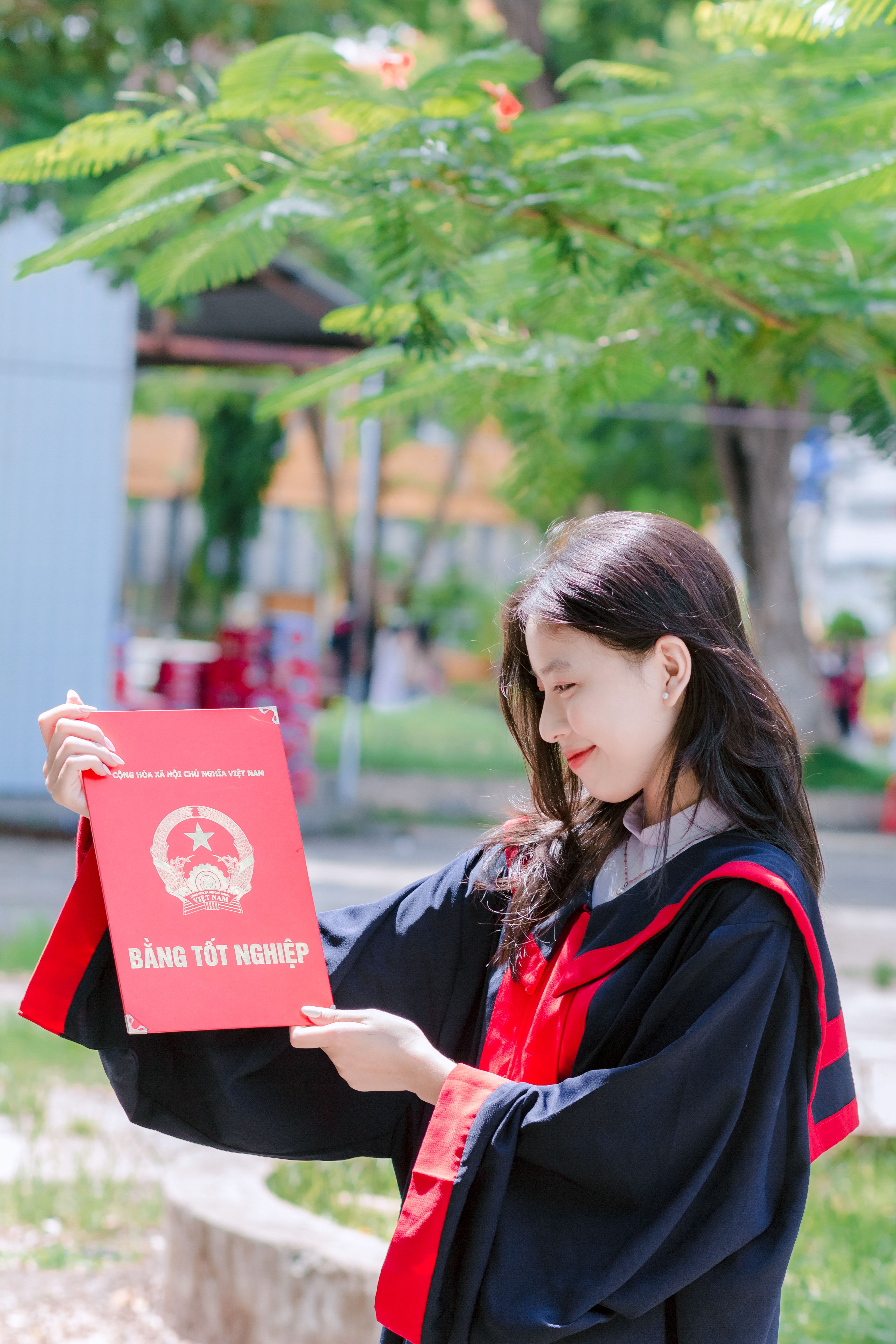 Smiling Girl in Graduation Gown Showing Diploma · Free Stock Photo