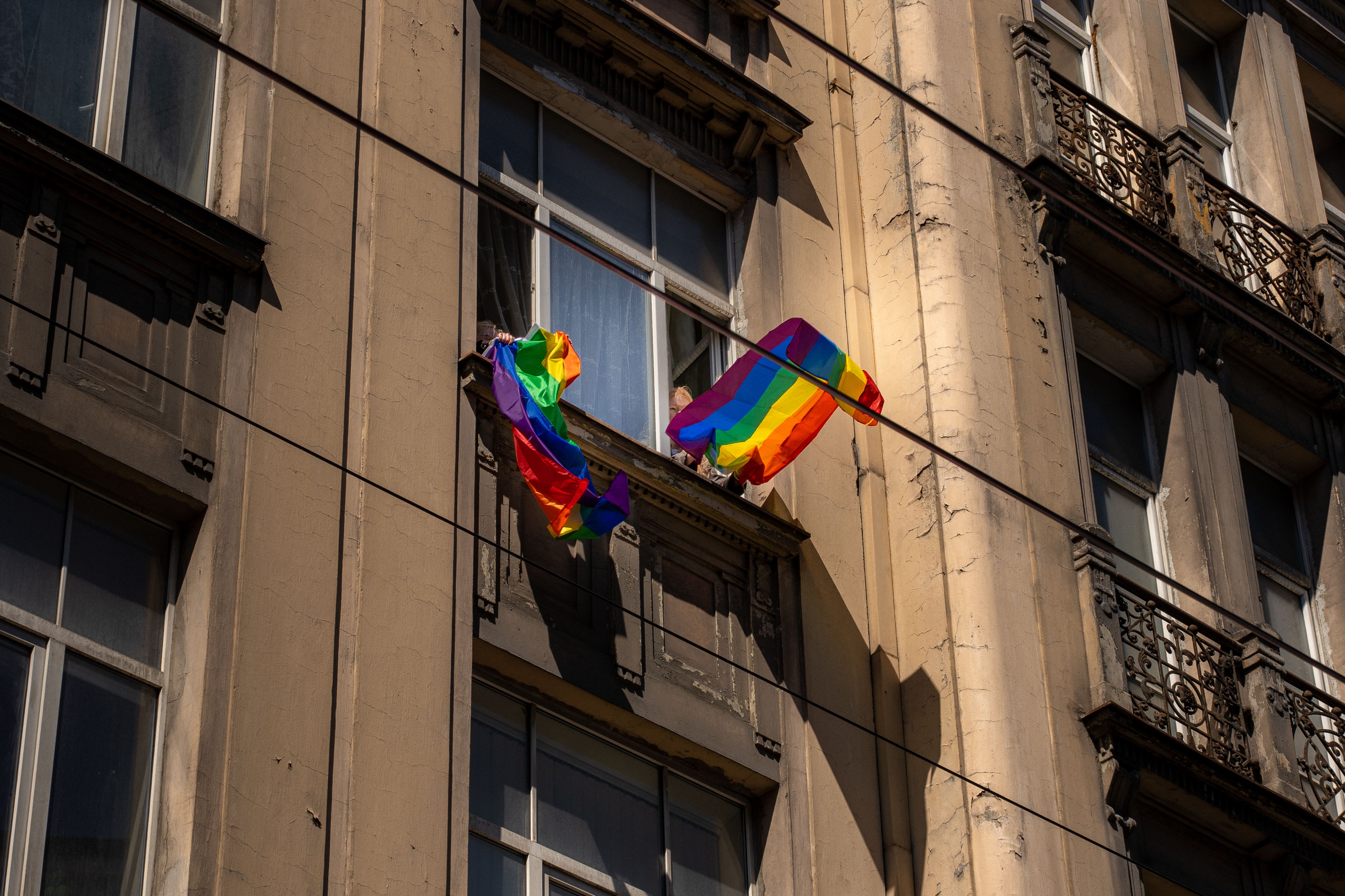 Low Angle Shot of Rainbow Flags Hanging from a Window of an Apartment ...