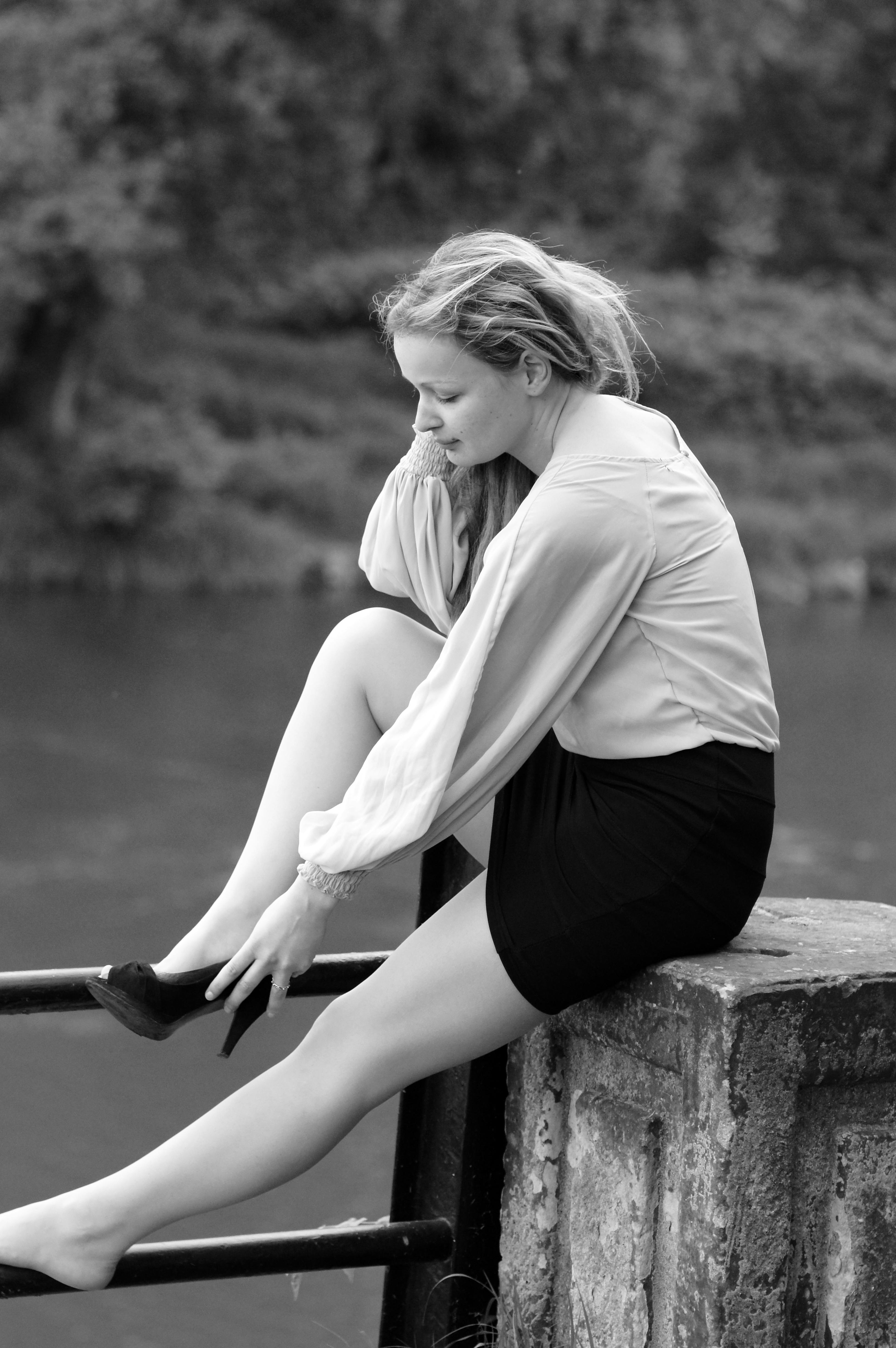 Woman in Strap Top Sitting on Stone Railing in Park · Free Stock Photo