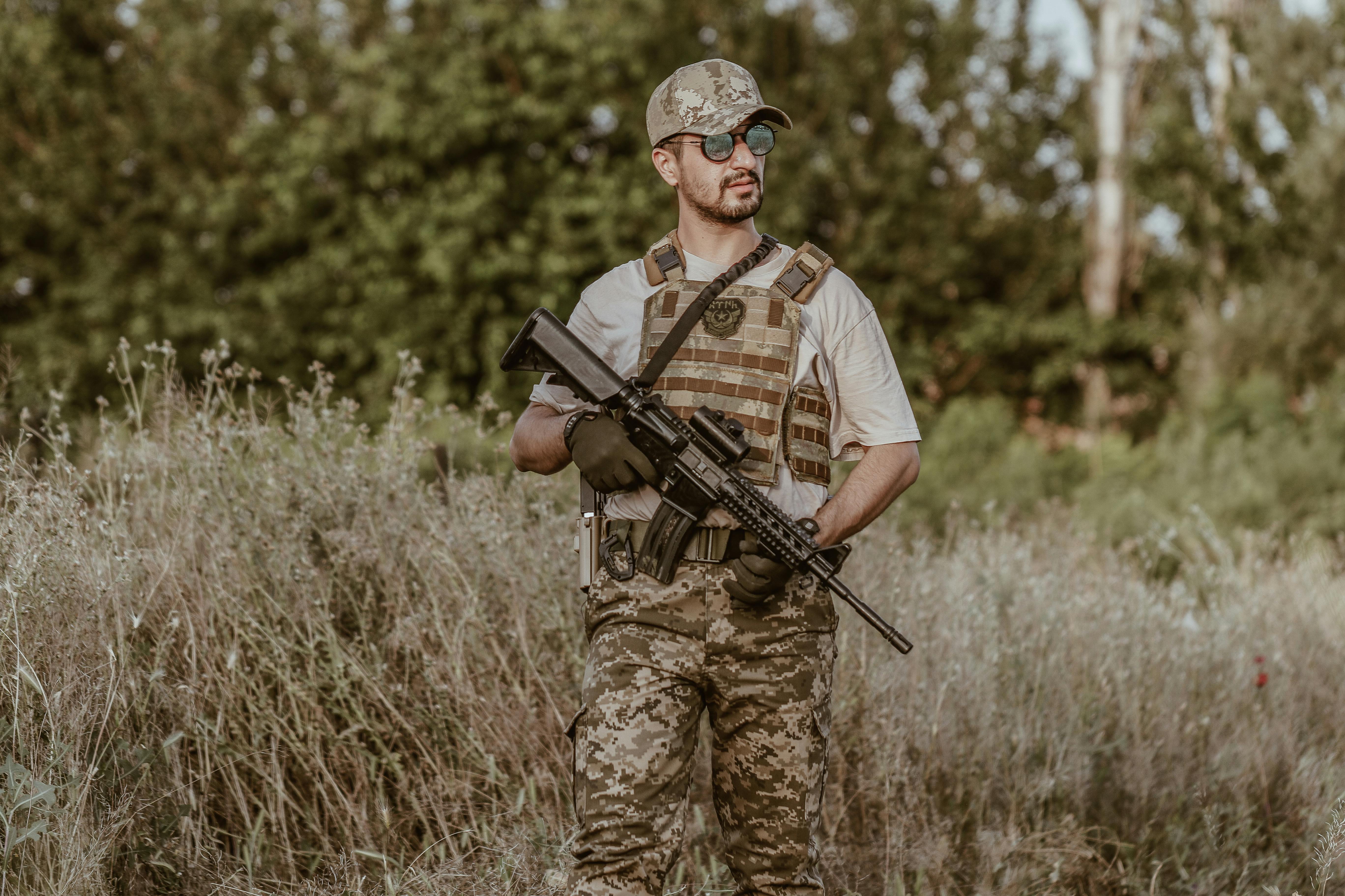 Man with Firearm on Grassland · Free Stock Photo