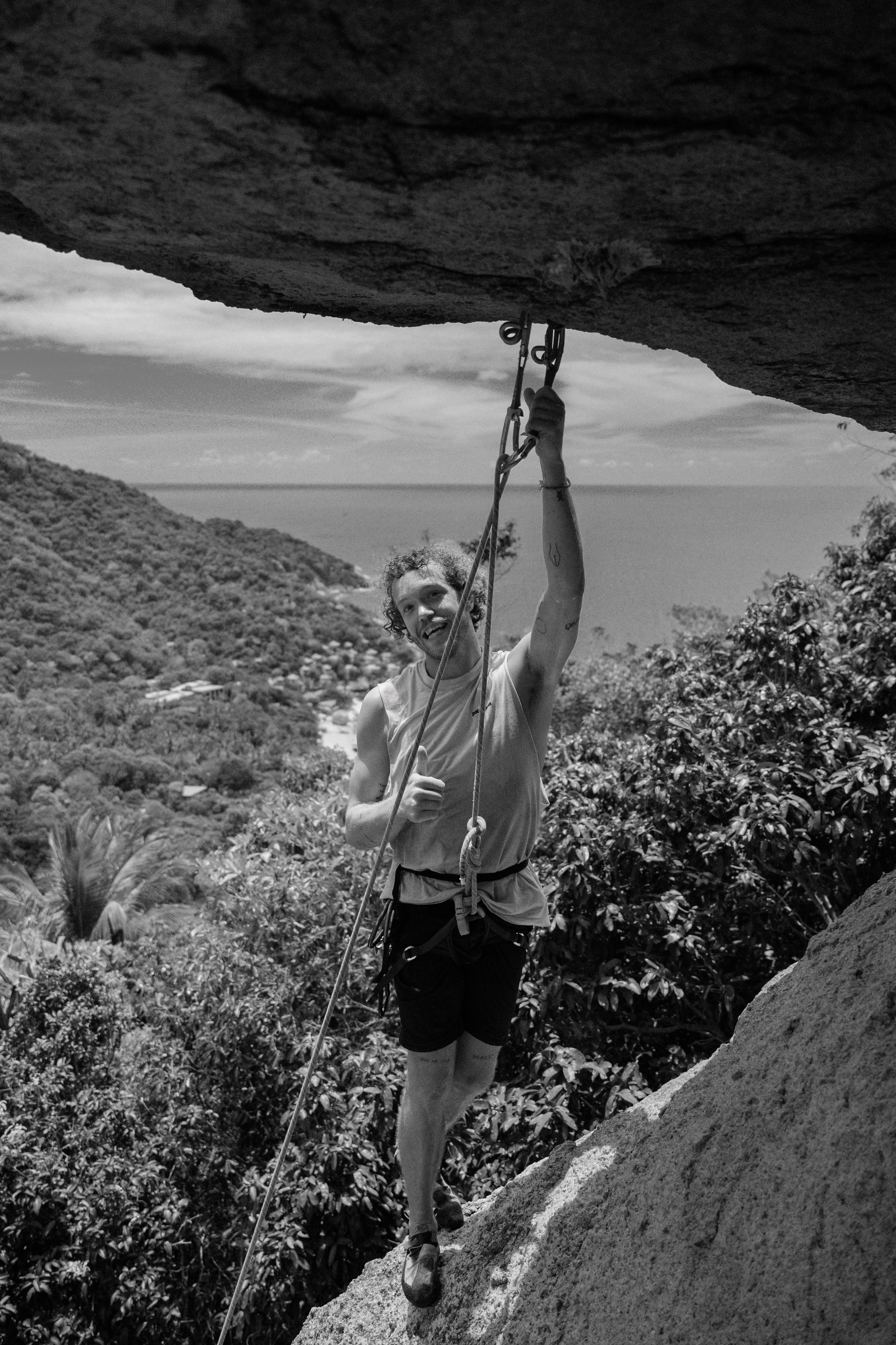 A black and white photo of a man climbing on a rock · Free Stock Photo