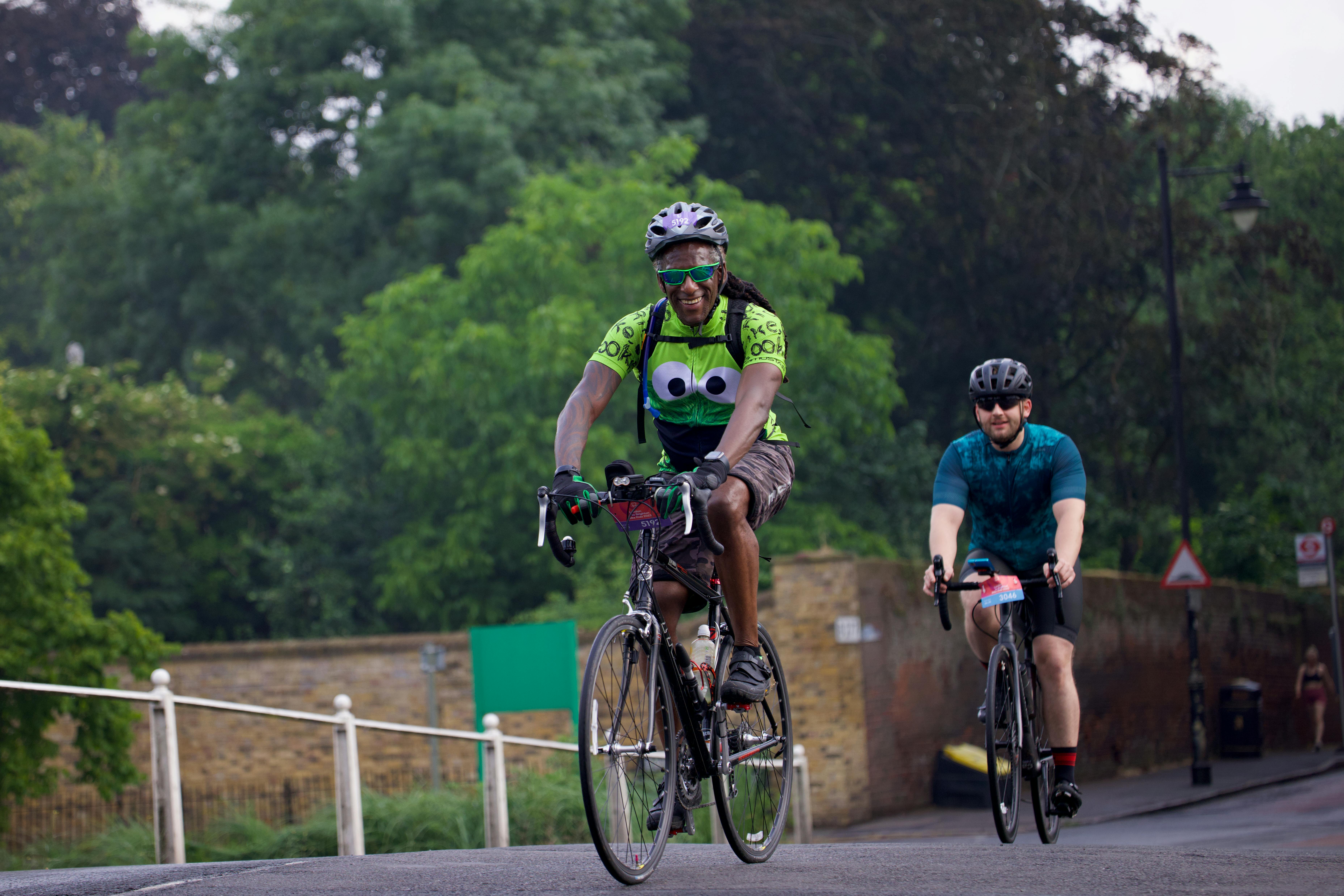 Two people riding bikes on a road with trees · Free Stock Photo