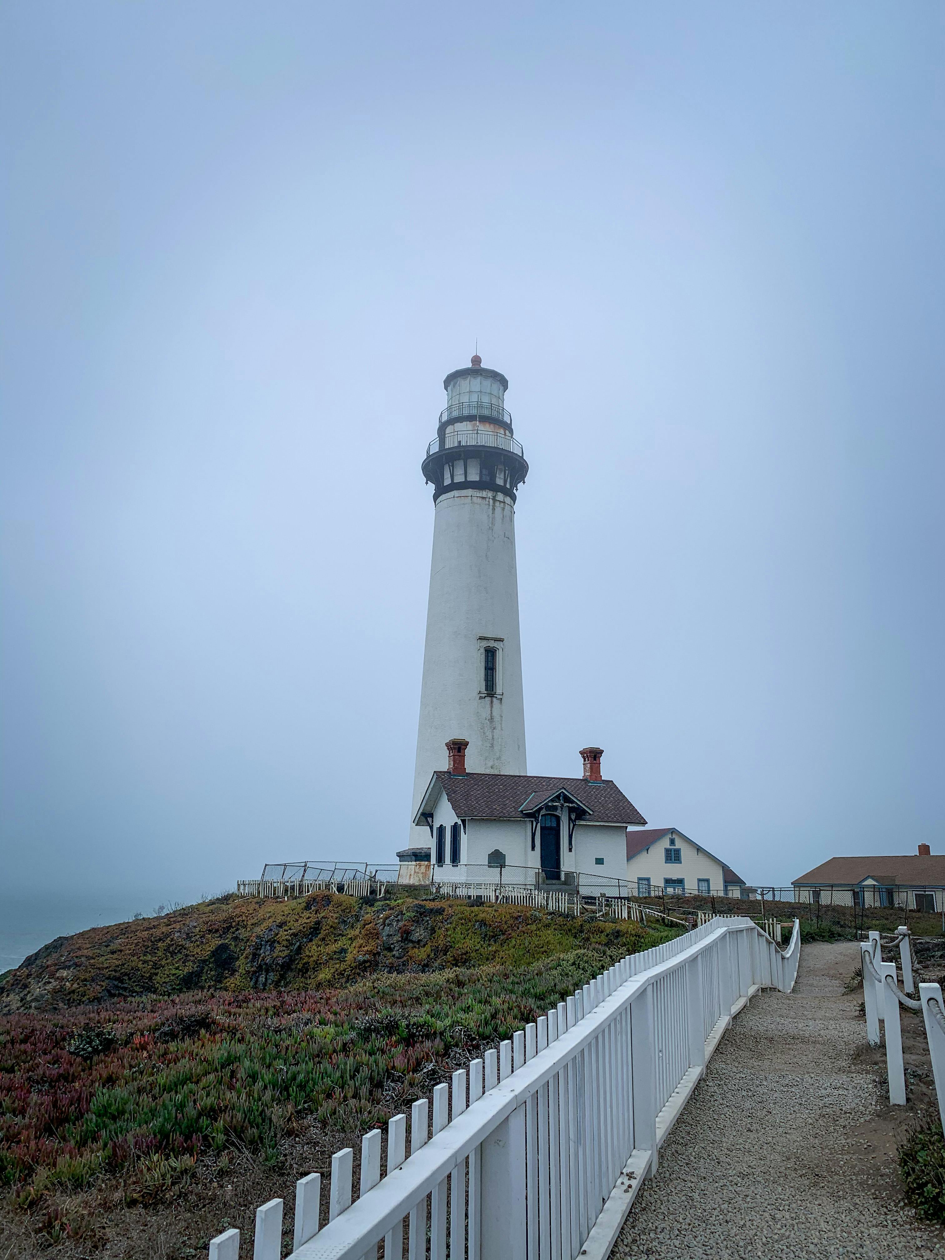 White and Black Striped Lighthouse Beside White House · Free Stock Photo