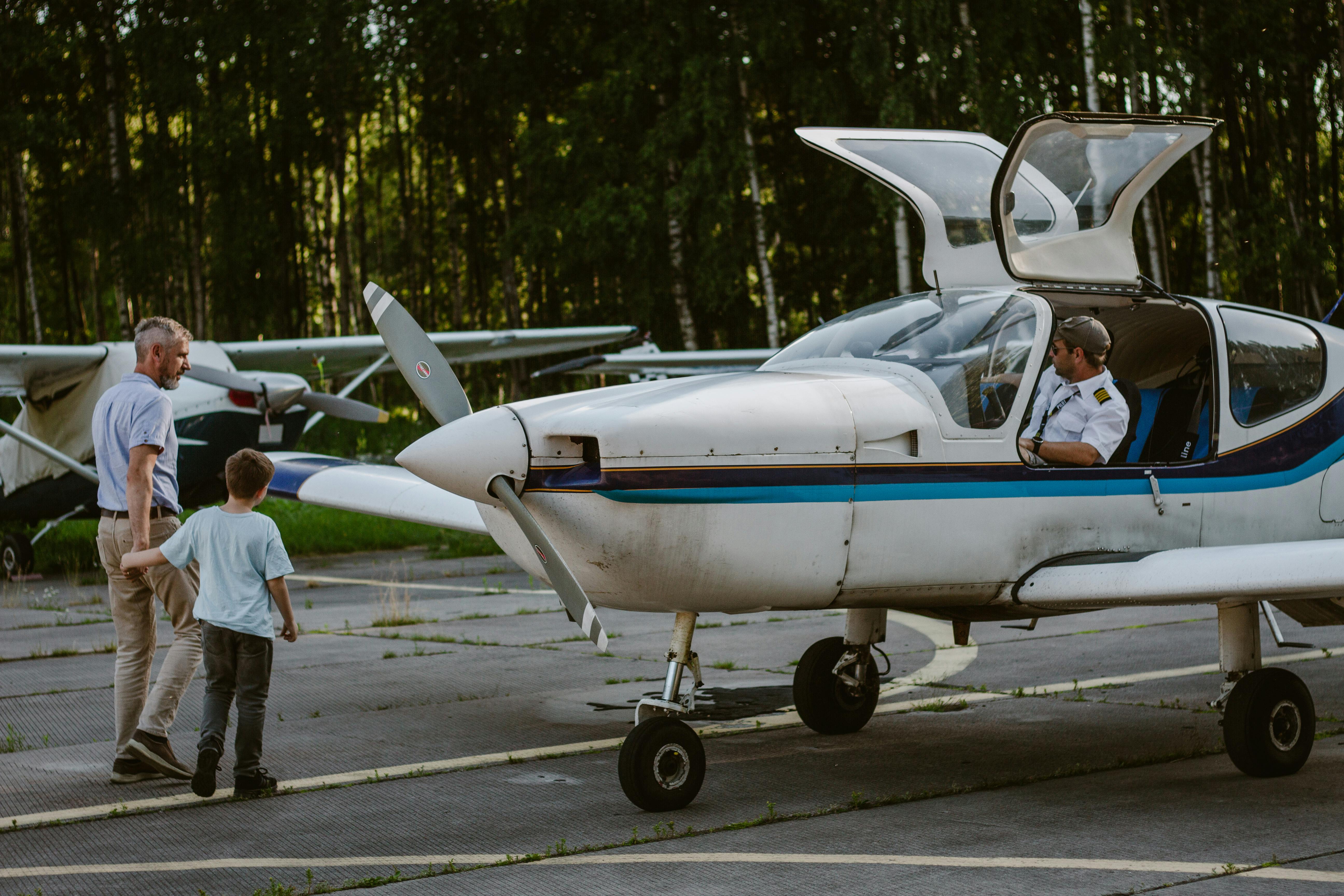 Father with Son Walking near Light Aircraft · Free Stock Photo