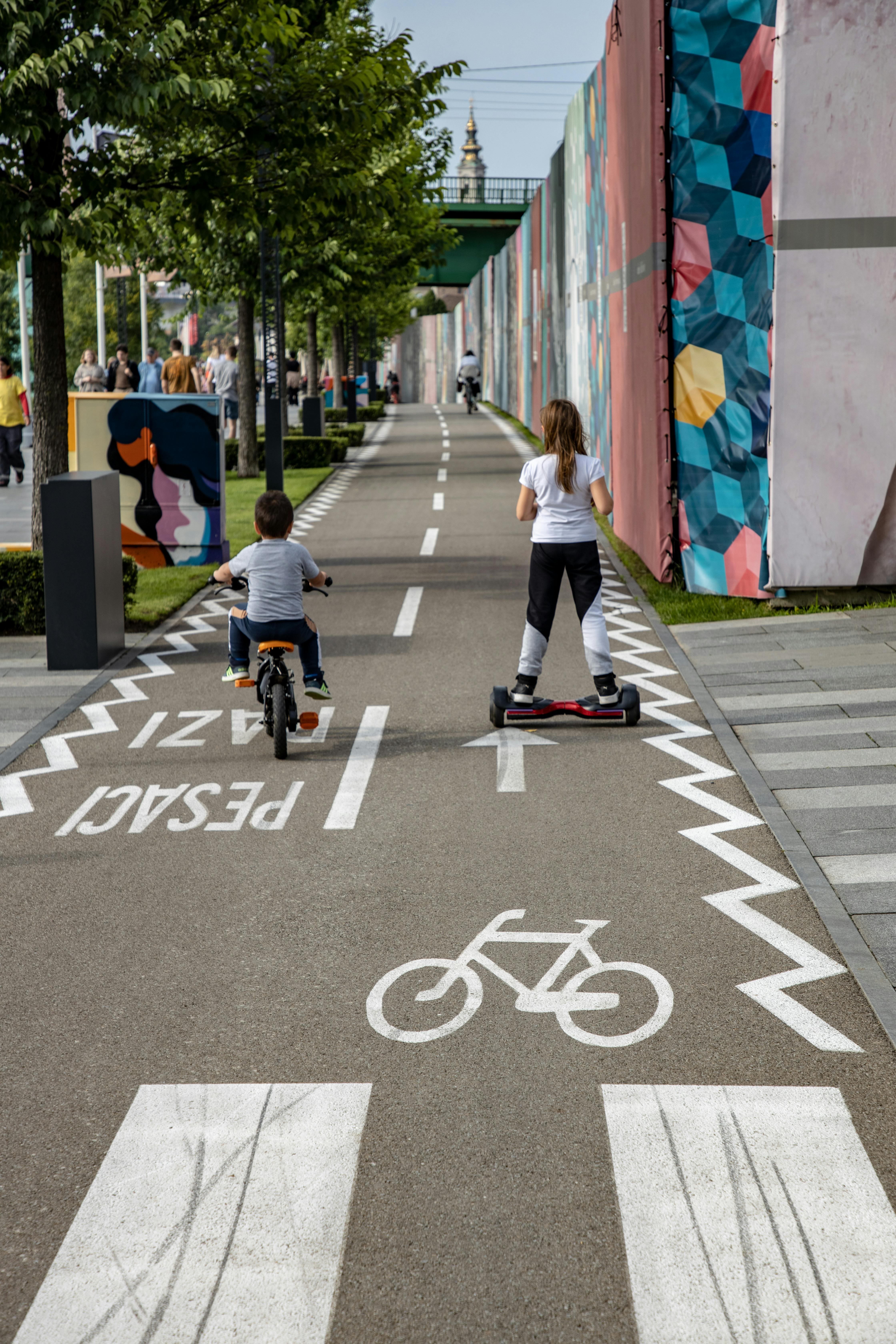 Girl on Sedgeway and Boy on Bicycle in City · Free Stock Photo