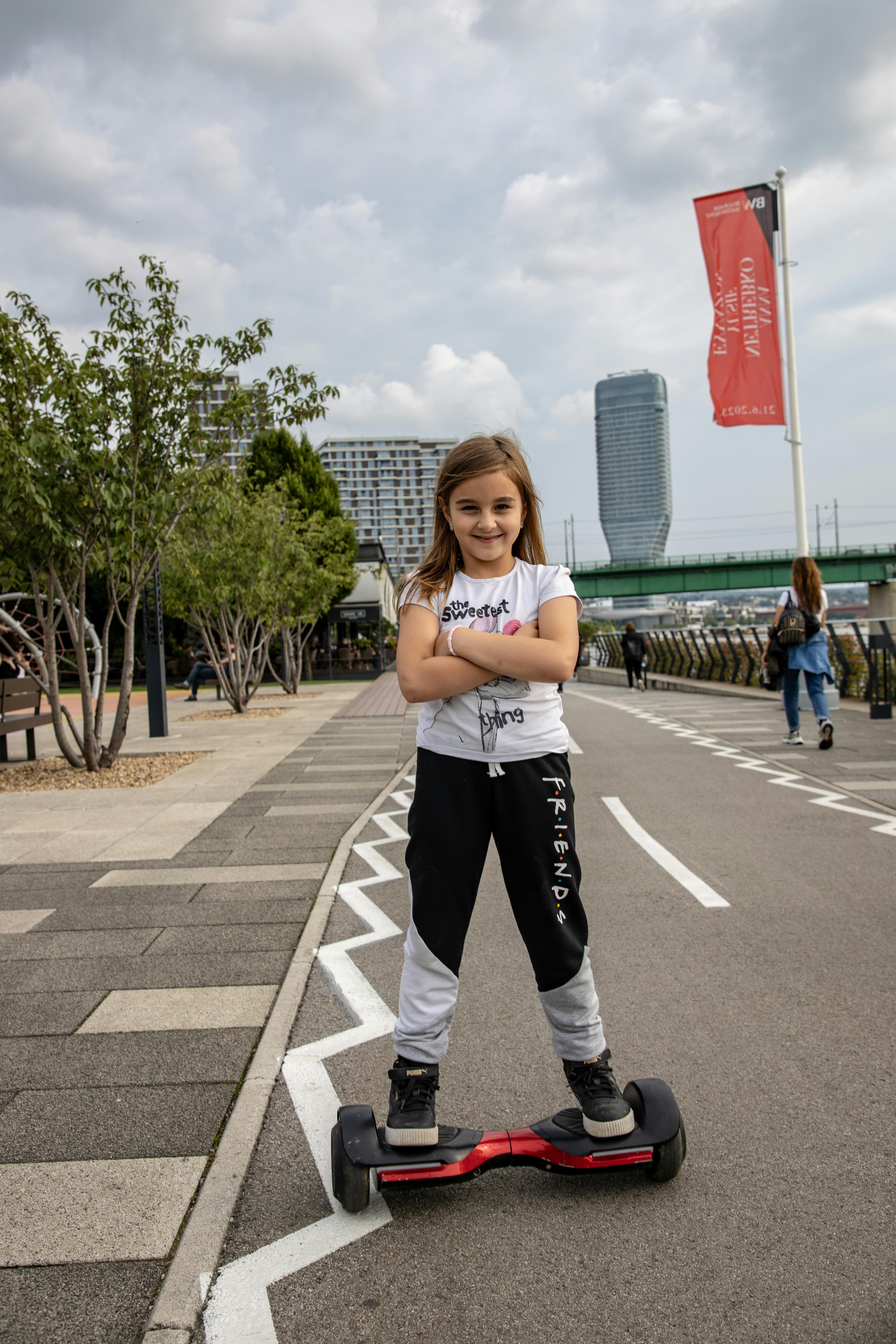 Smiling Gild Standing on Hoverboard · Free Stock Photo