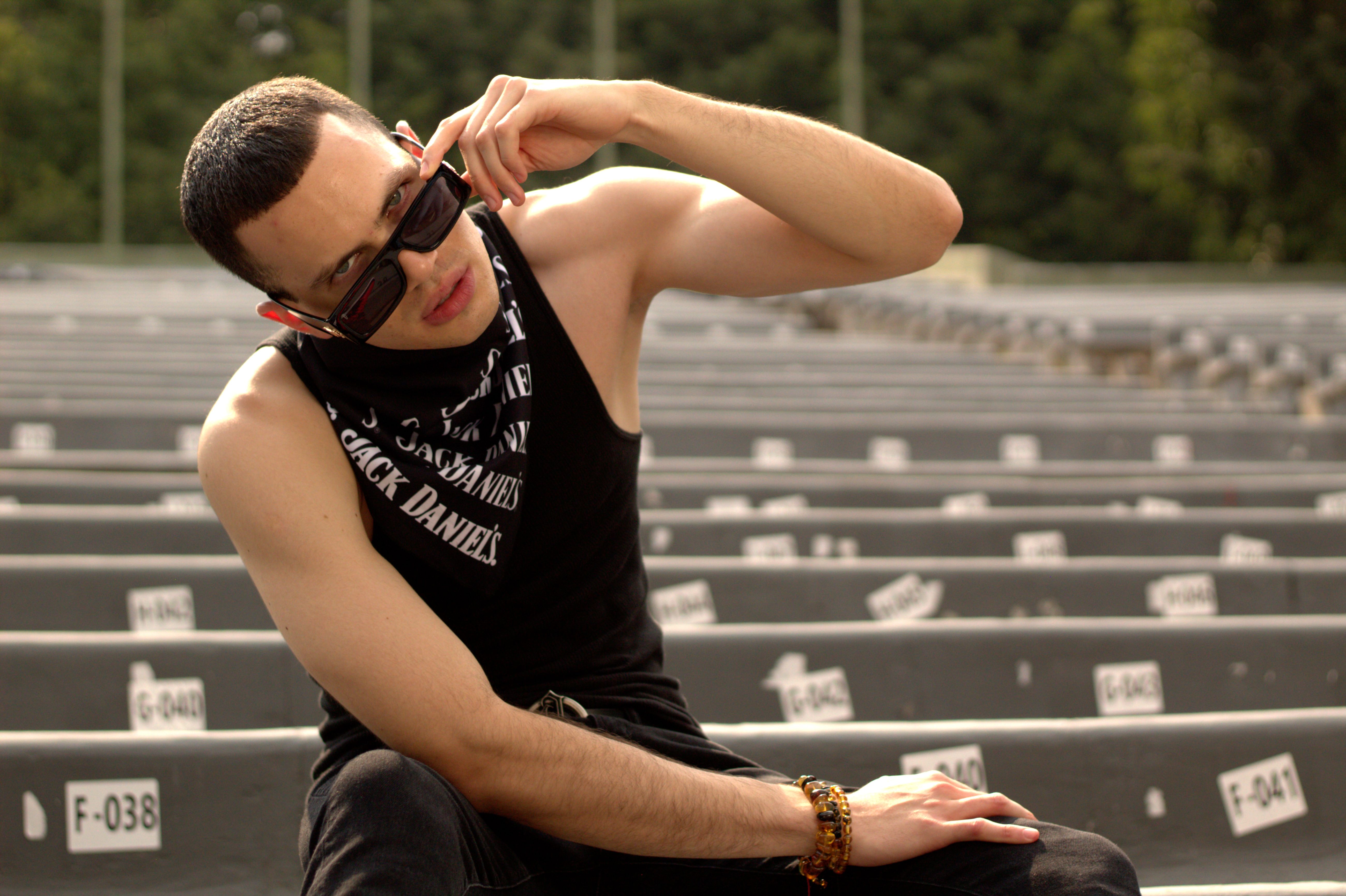 Man Sitting on Bleachers Taking off Sunglasses · Free Stock Photo