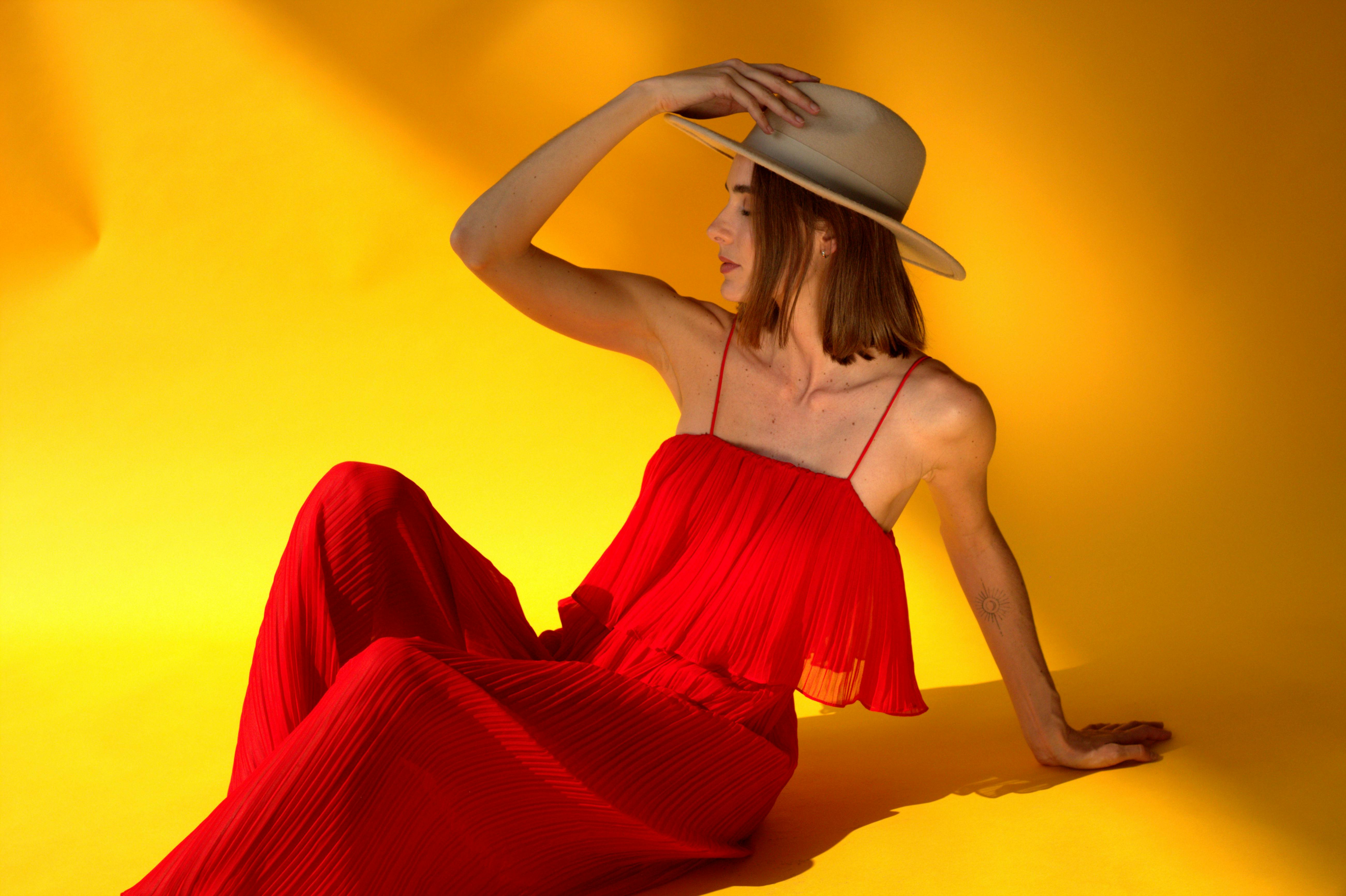 Woman in Red Sundress Sitting on Ground on Yellow Back · Free Stock Photo